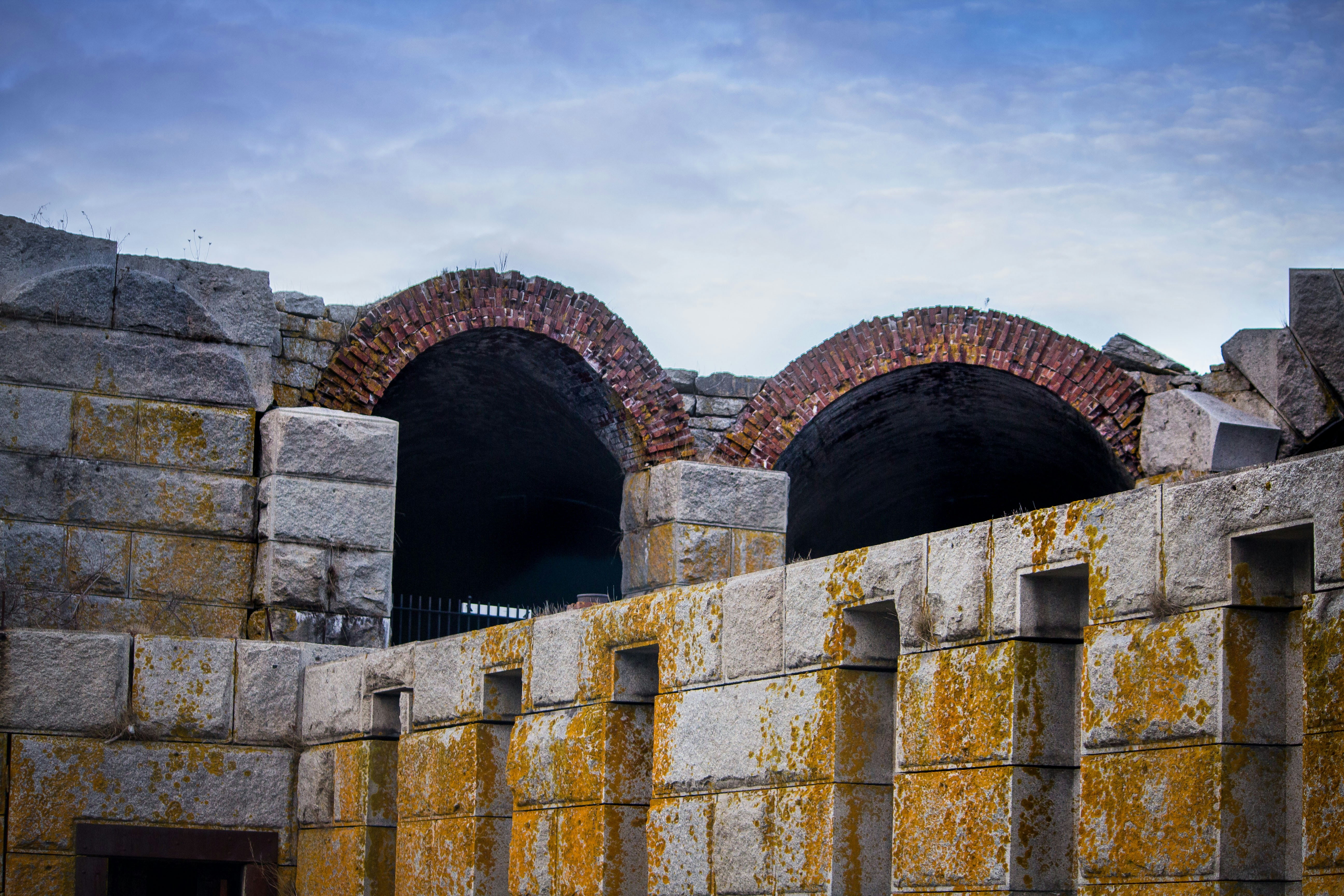 Weathered stone walls and arches reveal the remnants of a historic structure, showcasing intricate textures and patterns. Moss and lichen add a touch of nature's artistry.