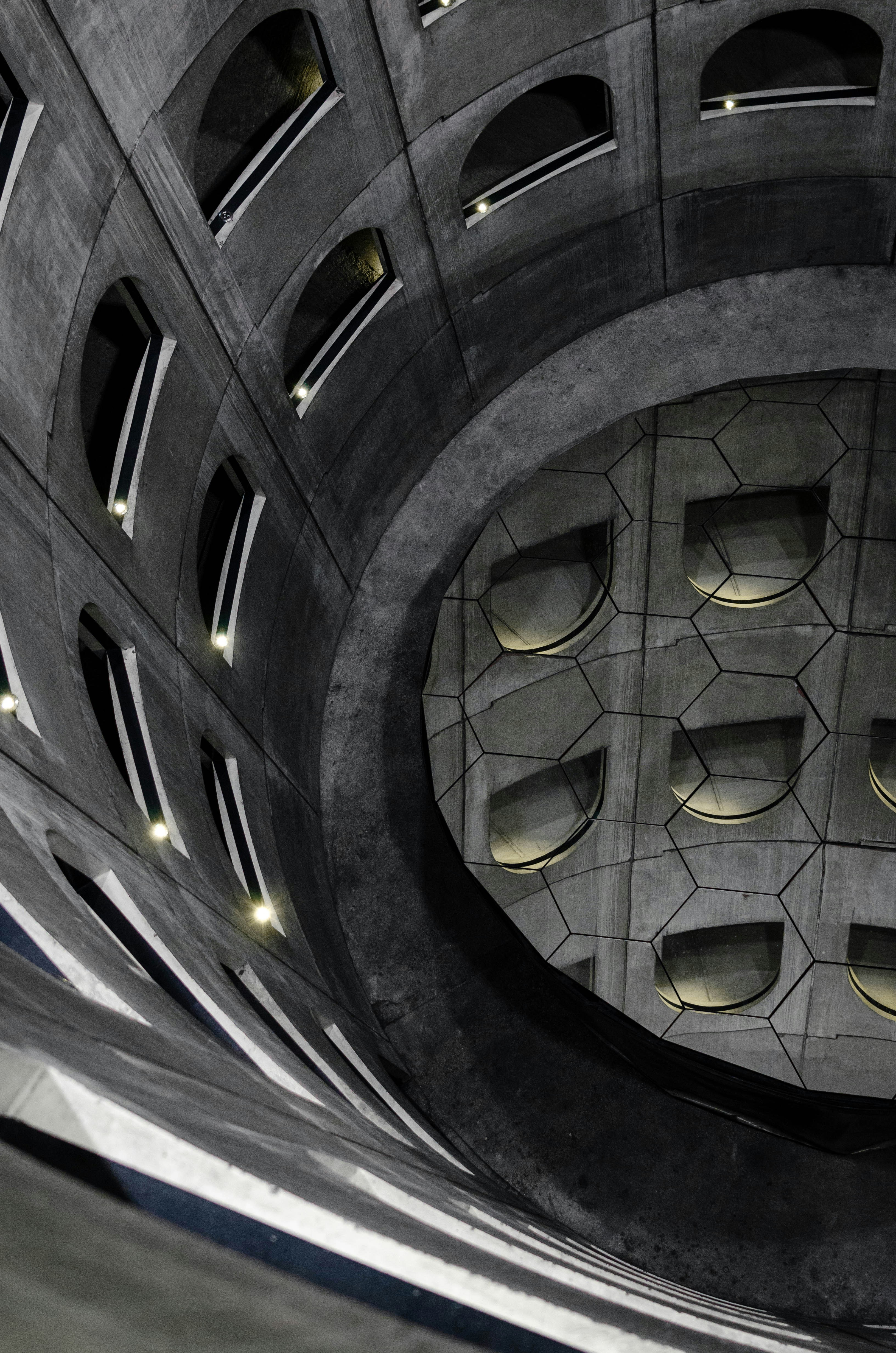 Abstract view of a spiraling concrete structure with geometric patterns and soft lighting illuminating the interior walls.