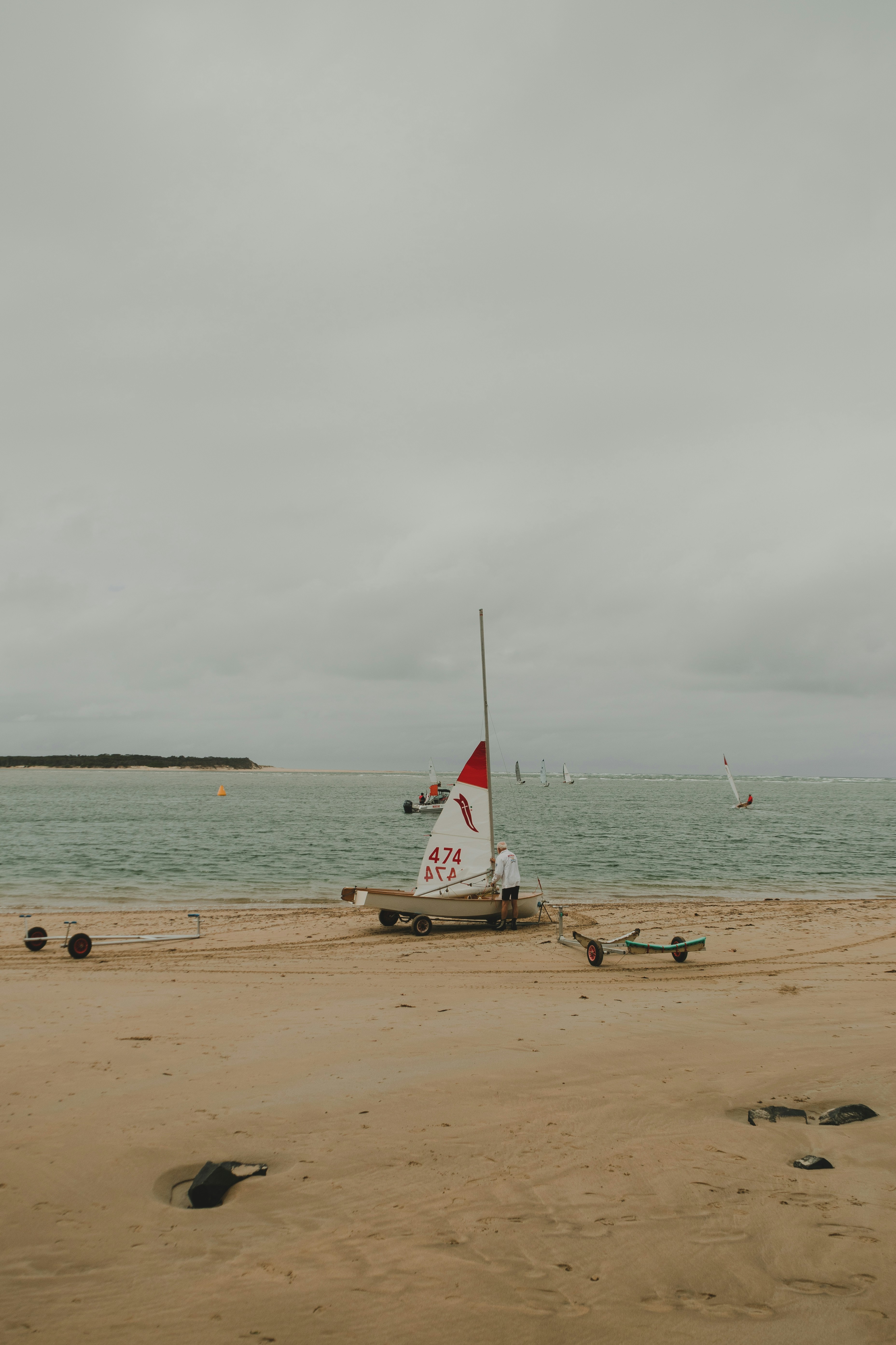 Red-Topped Sailboat Resting on Wind-Washed Beach