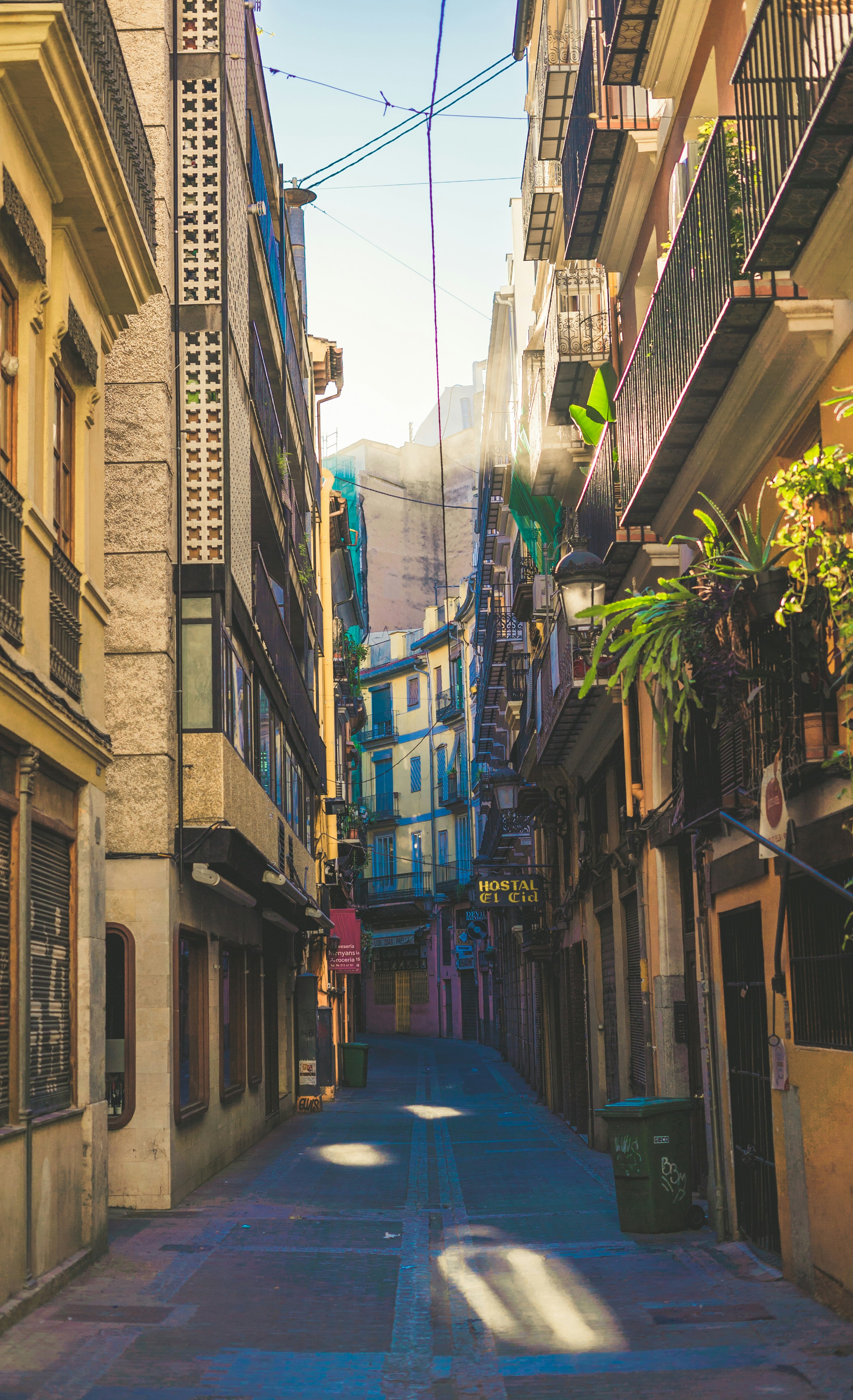Cobalt Horizon: A Sunlit Calle Narrowing Toward a Blue Facade