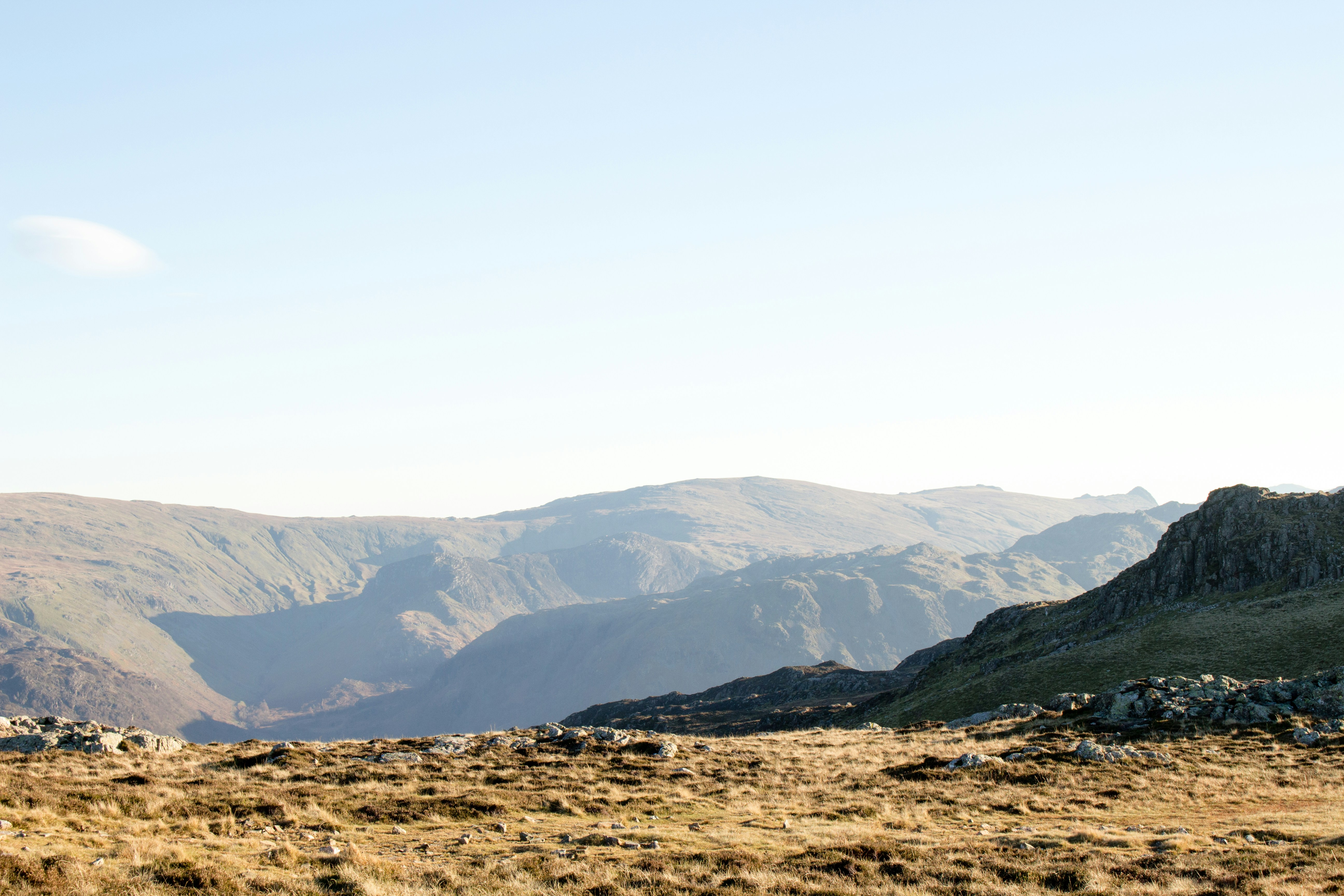 Expansive highland vista showcasing rolling hills and distant mountains under a clear sky. The rugged terrain invites exploration.