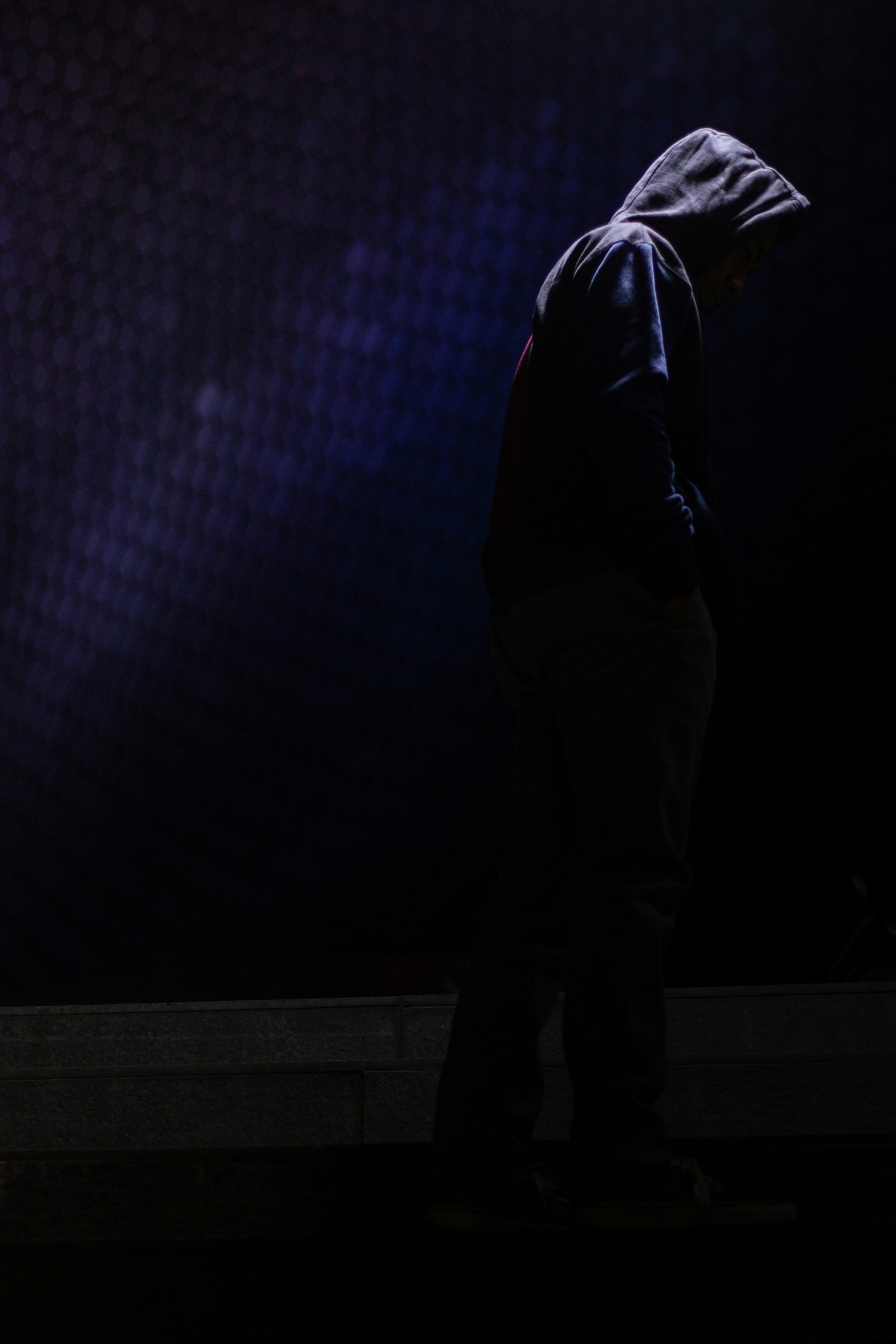 Hooded Silhouette on a Cobalt-Lit Stage Against a Dotted Purple Backdrop