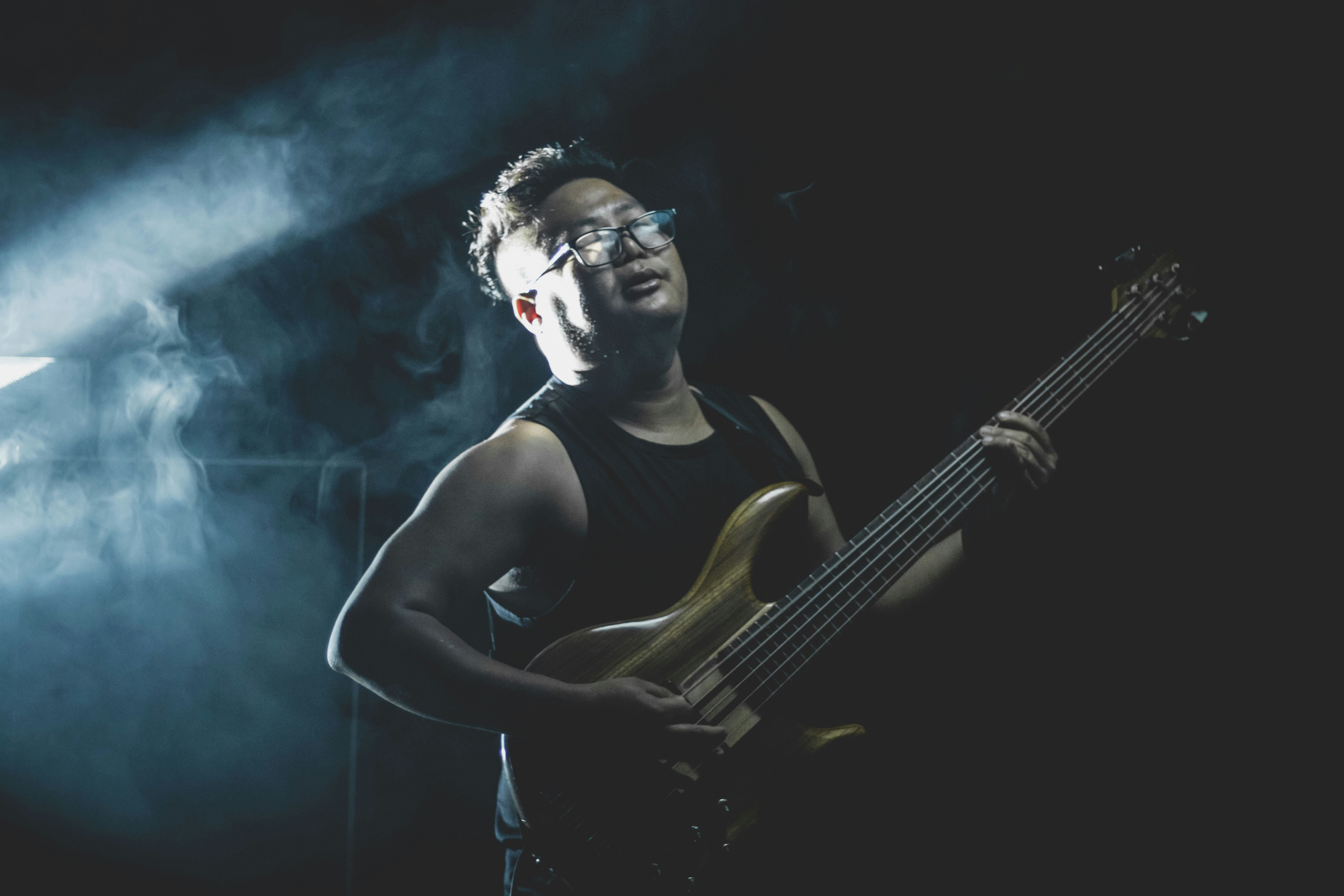Bassist passionately performing under dramatic lighting with smoke effects, highlighting the energy of live music.