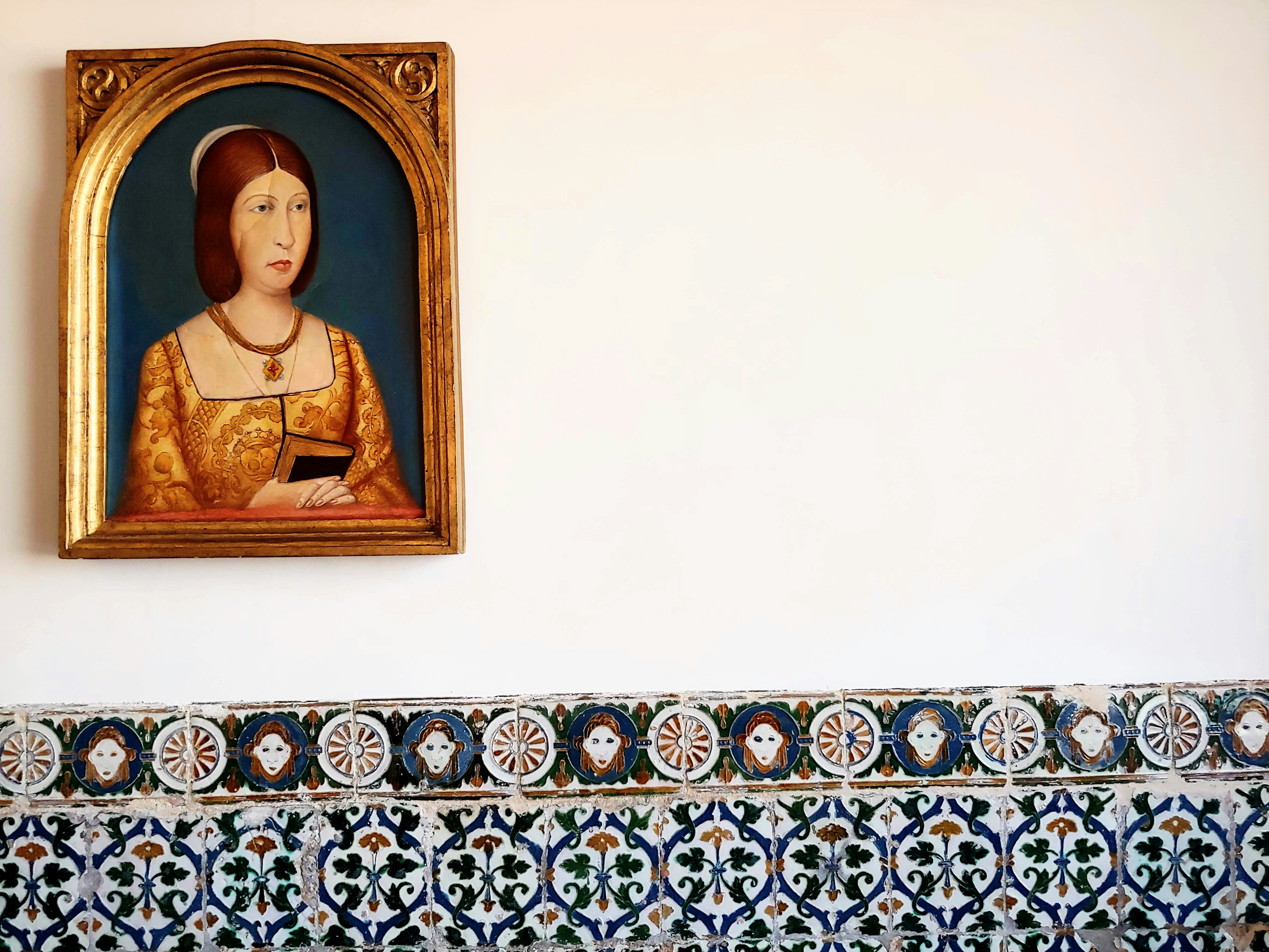 Framed portrait of a historical figure above ornate blue and white tiled wall.