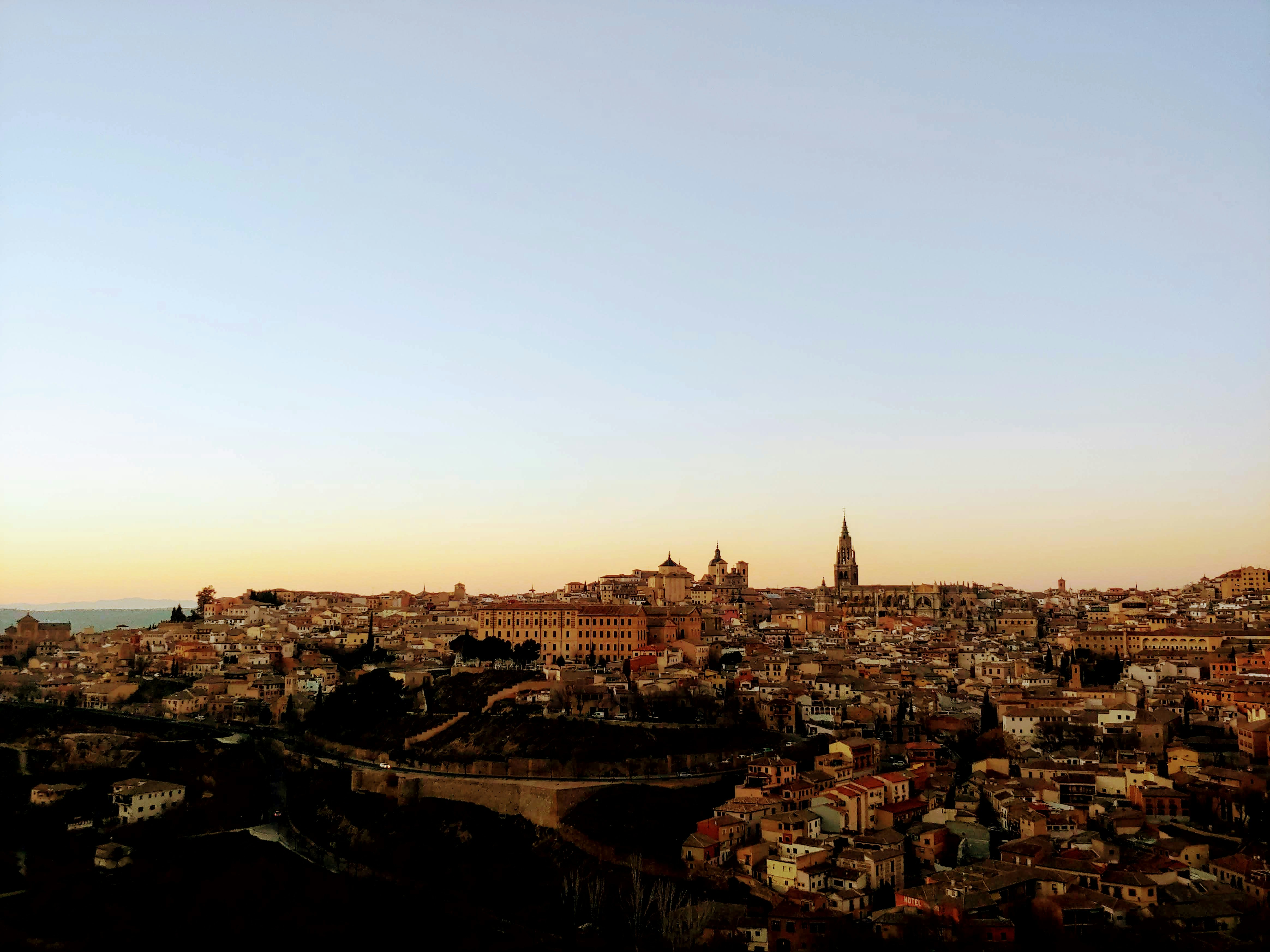 Panoramic view of a historic cityscape bathed in warm evening light under a clear sky.
