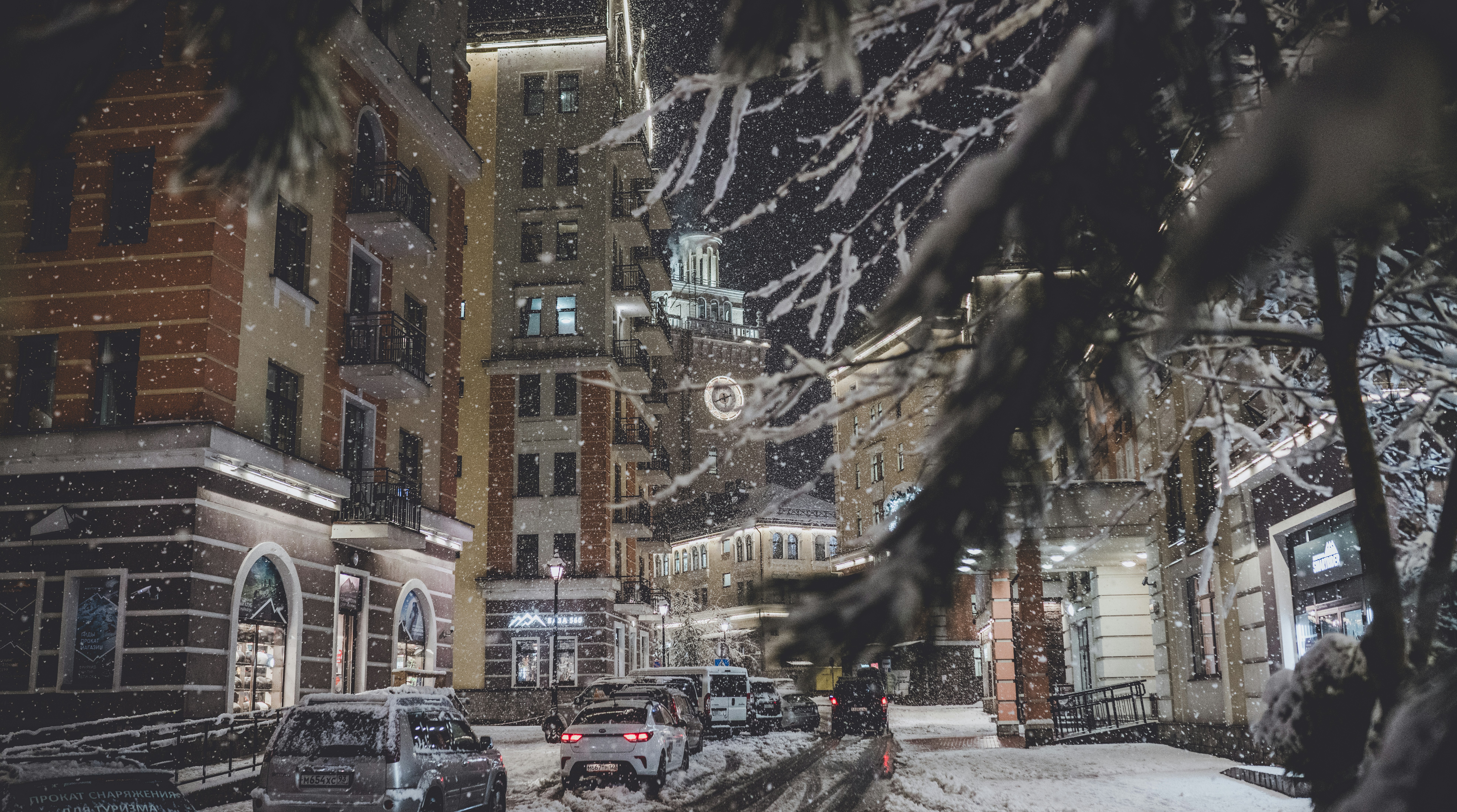 Snow-covered streets illuminated by warm lights in a bustling city at night, capturing the essence of winter's embrace.