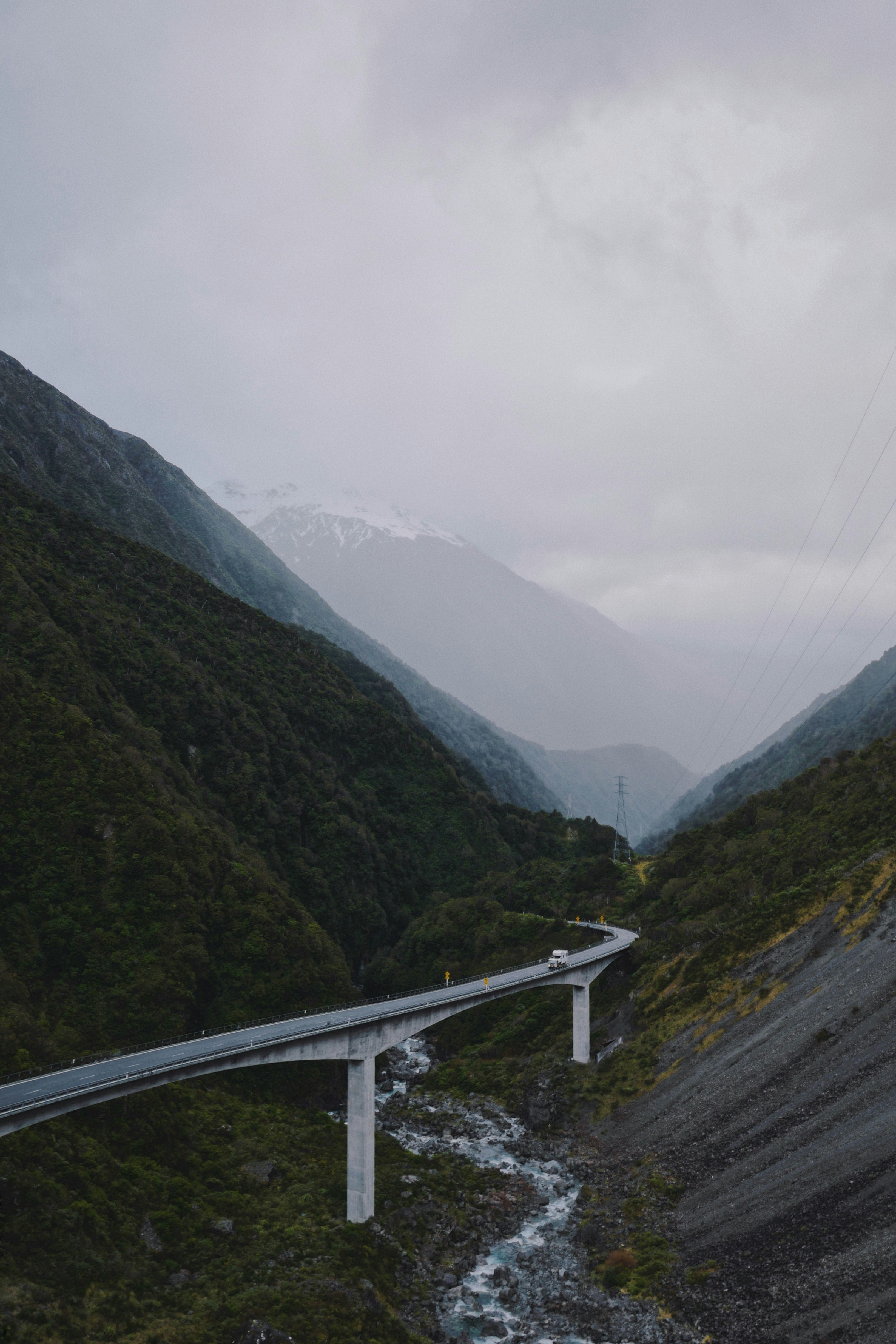 Bridge in between mountains under grey sky photo – Free Grey Image on ...