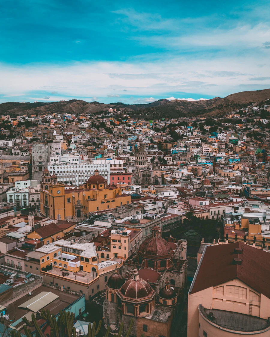 Clustered colonial domes and colorful hillside buildings beneath a wide blue sky, emphasizing dense urban architecture and layered rooftops.
