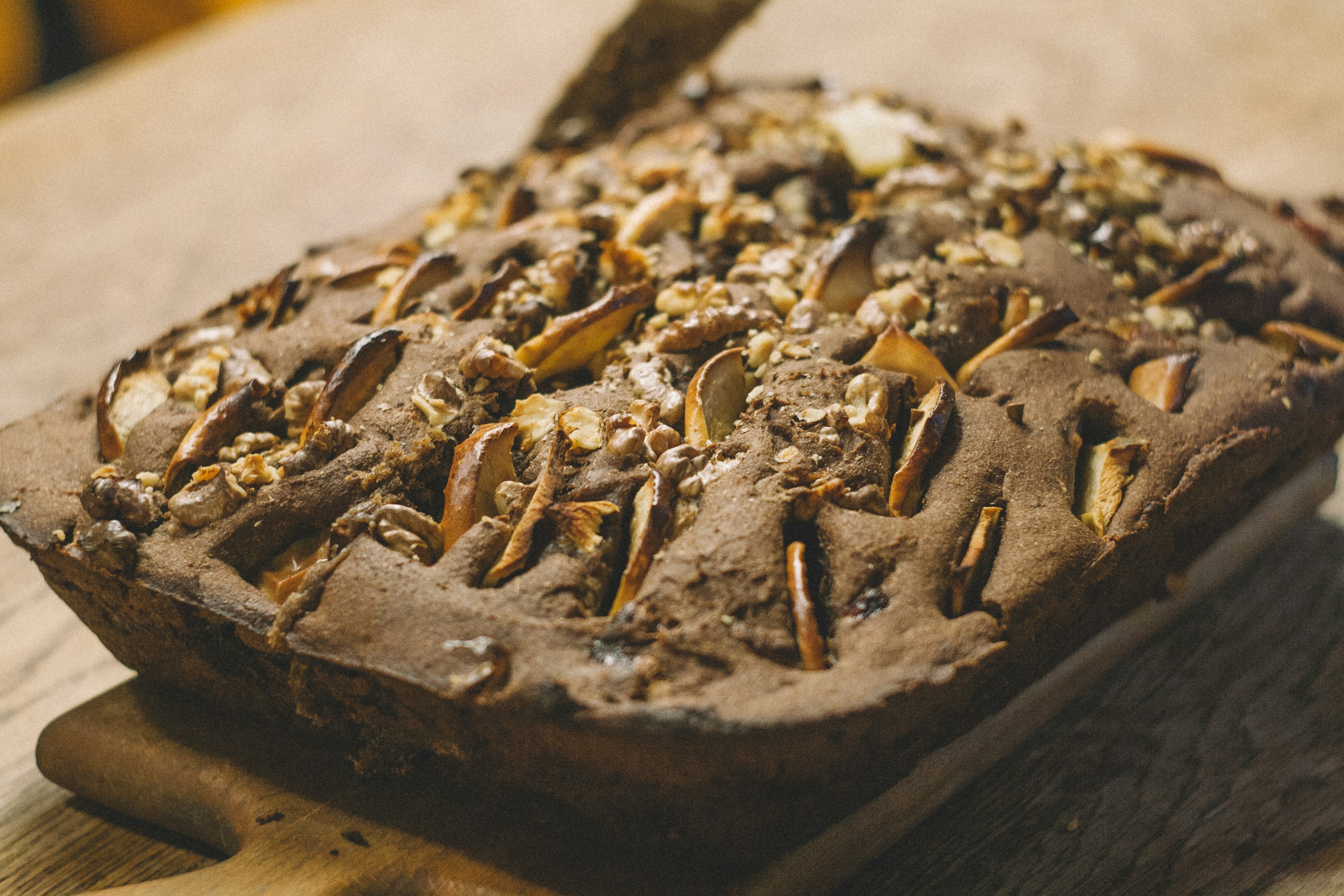 Delicious apple cake topped with nuts, showcasing a textured surface and warm tones on a wooden board.