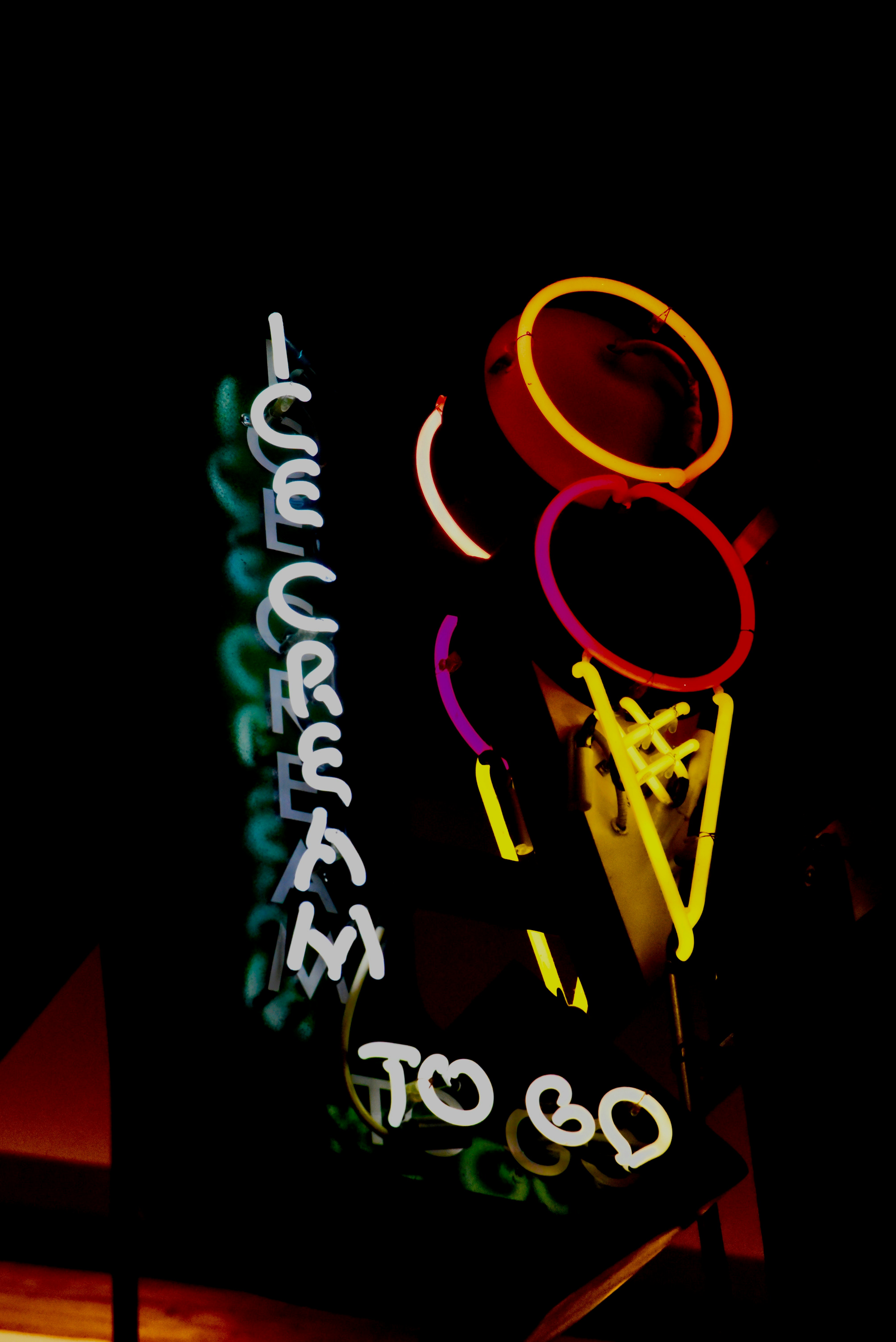 Vibrant neon sign advertising ice cream, featuring colorful circles and playful typography against a dark backdrop.