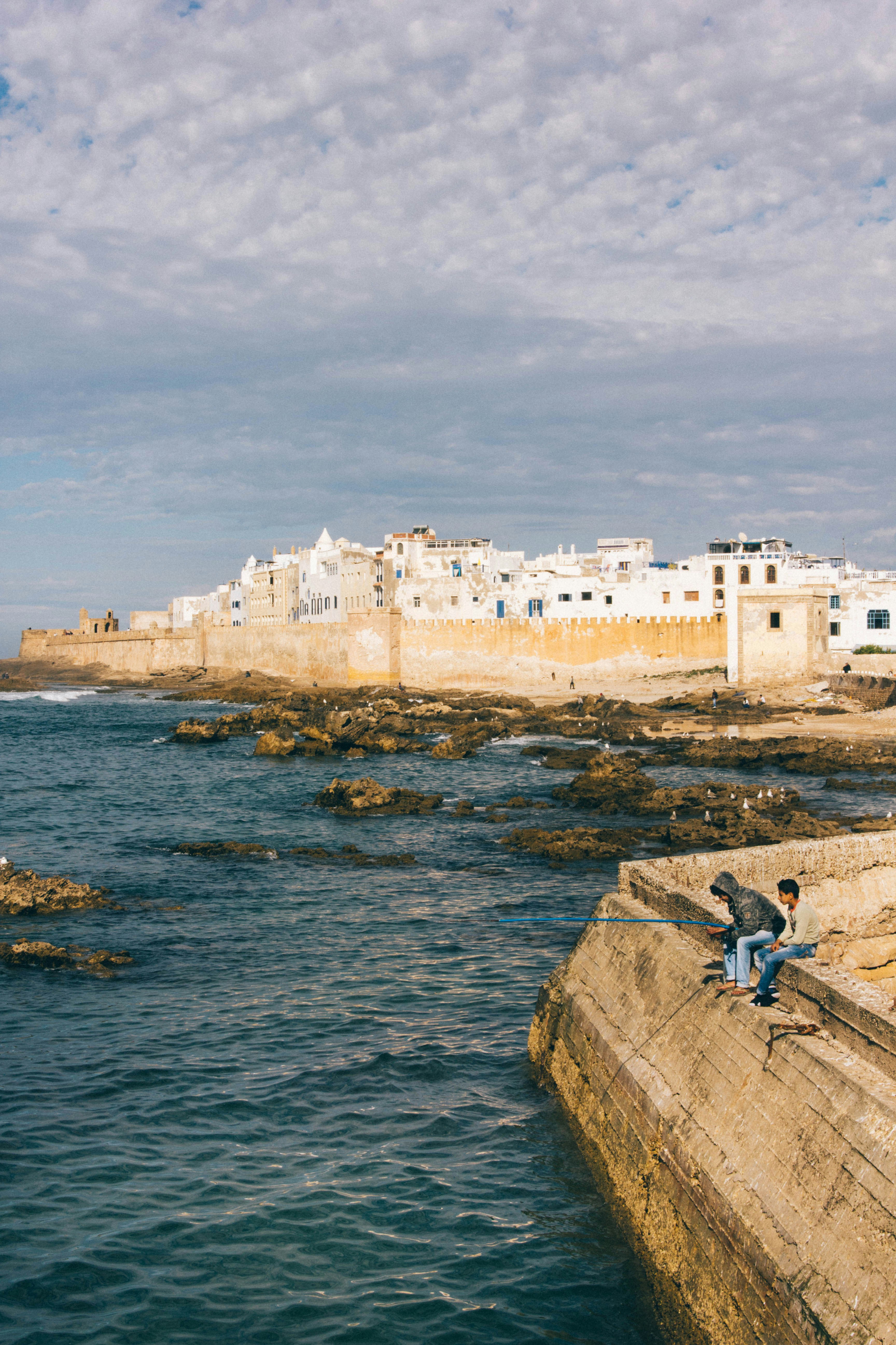 Sunlit Bastion by the Seafront: Fishermen at the Seawall