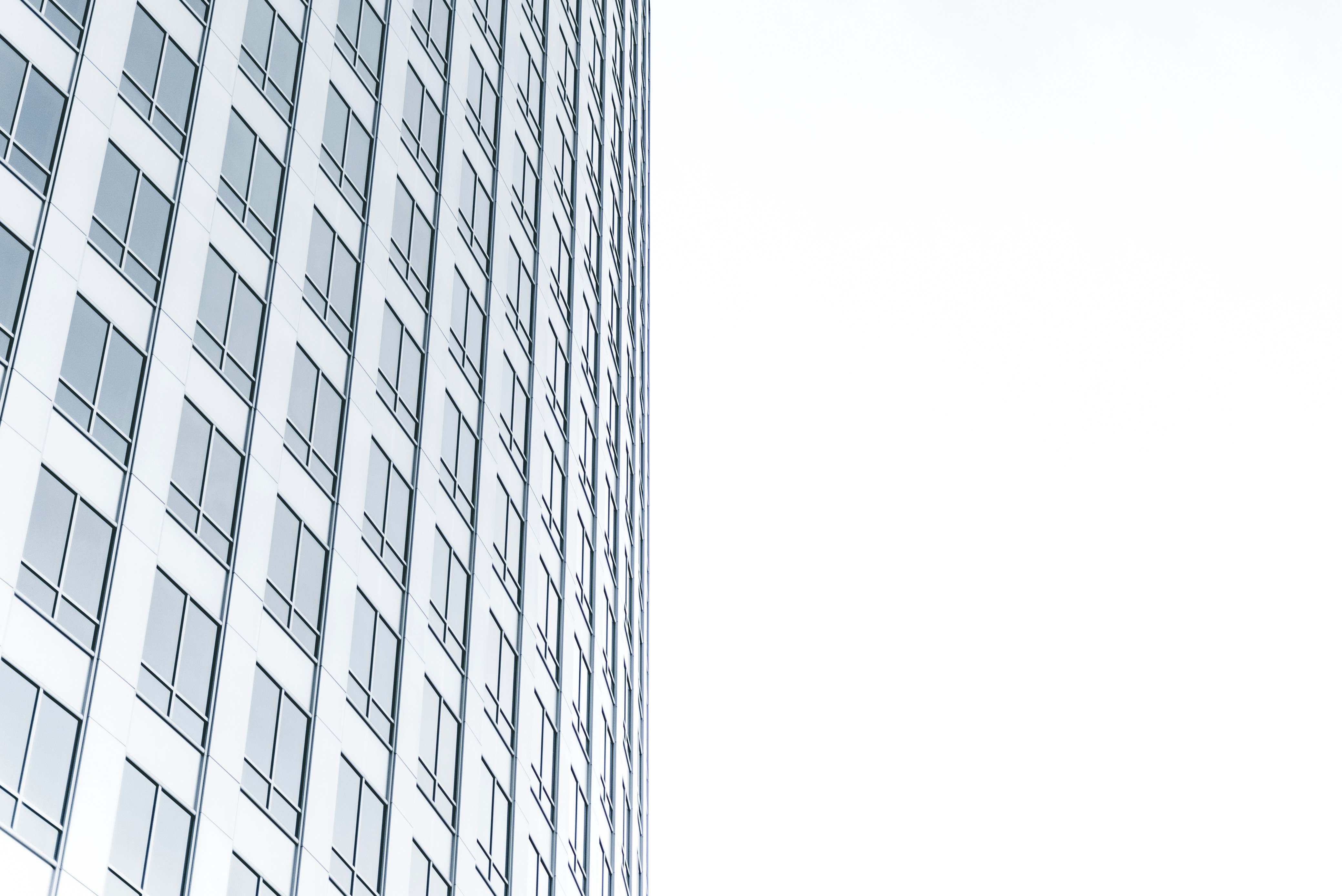 Tall glass building with a sleek façade reflecting the sky, showcasing modern architectural design.