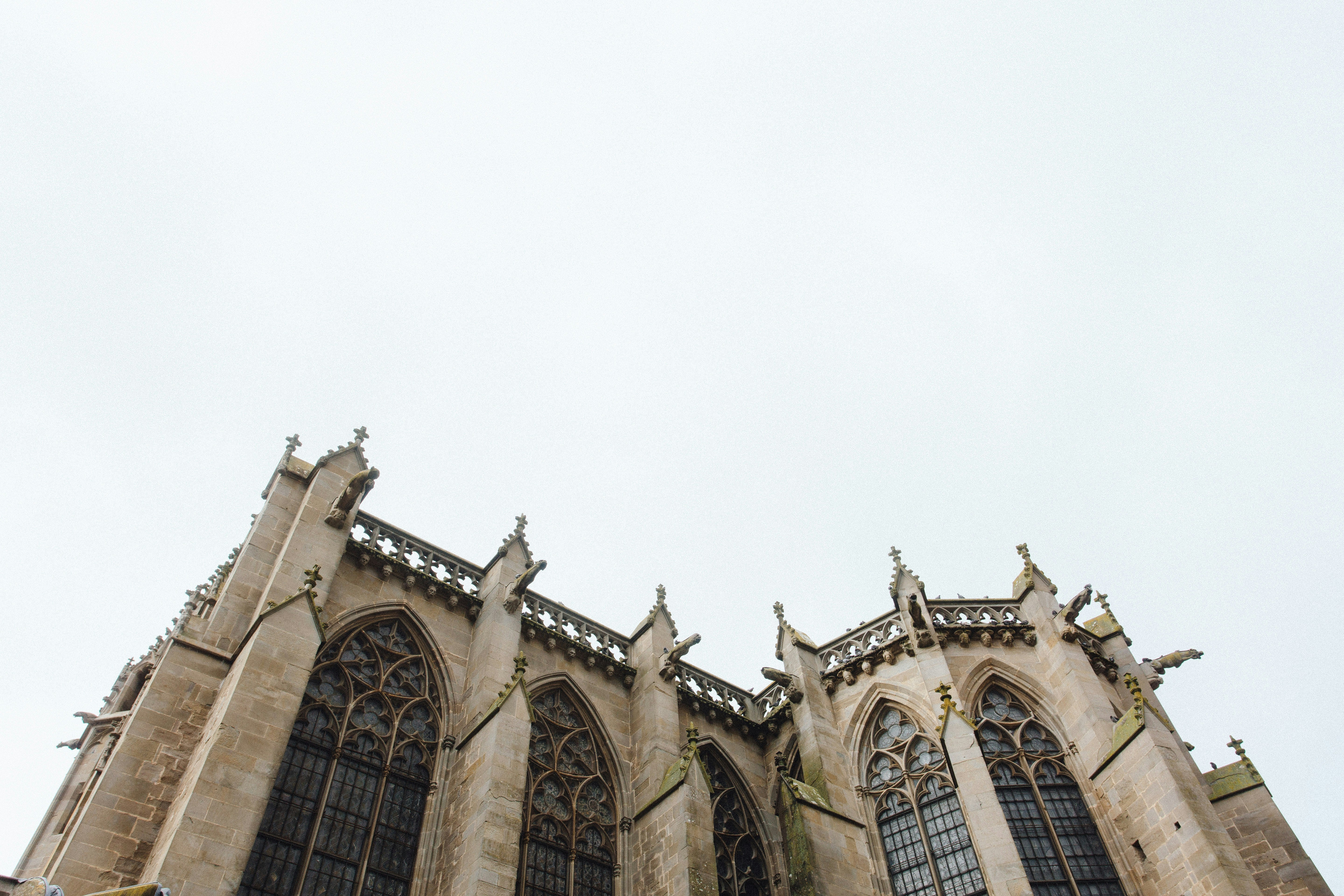 Low-angle view of a Gothic-style building with pointed arches and intricate stonework against a cloudy sky.