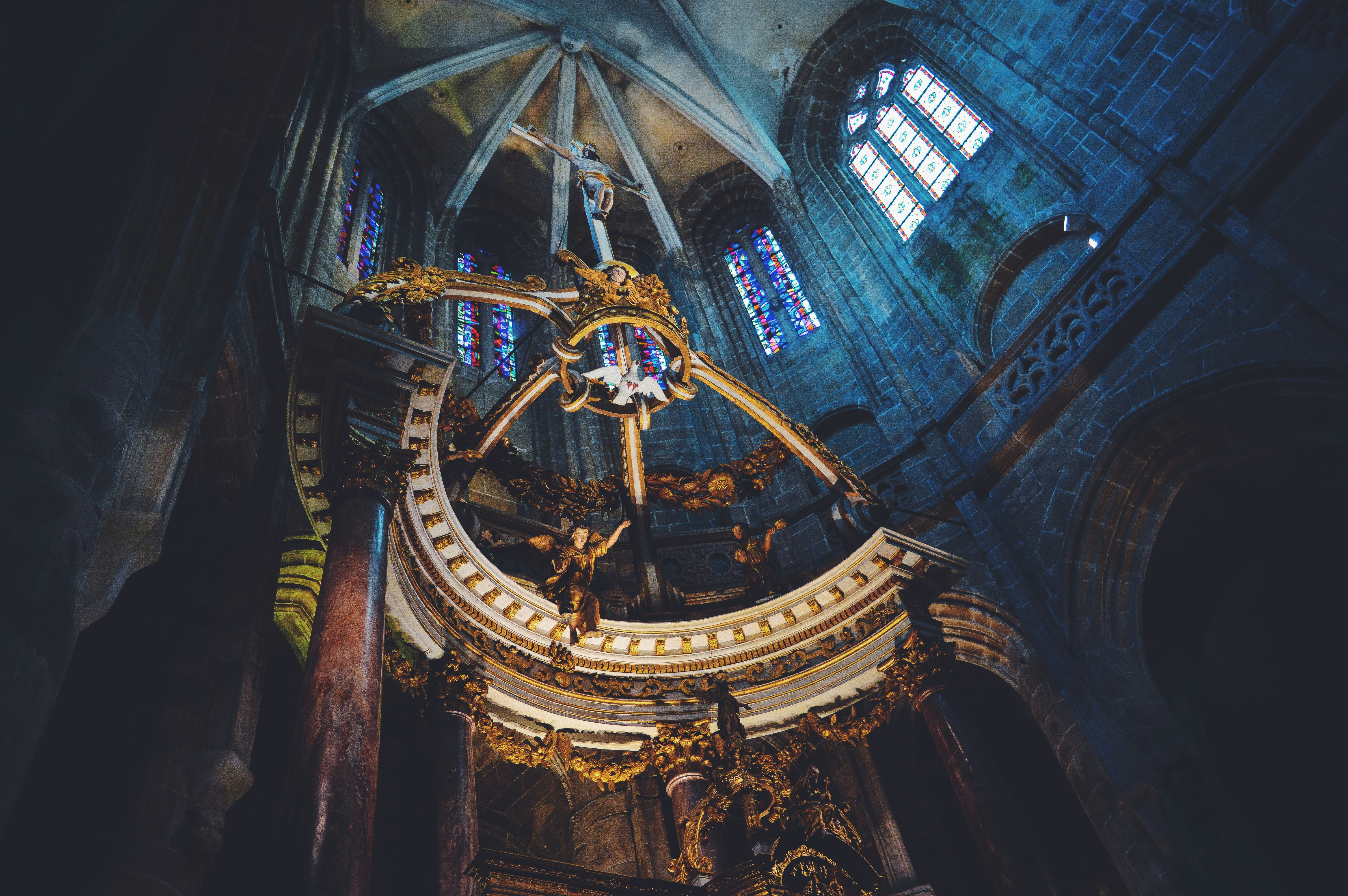 Ornate Gothic ceiling with intricate arches and stained glass windows illuminating the space.
