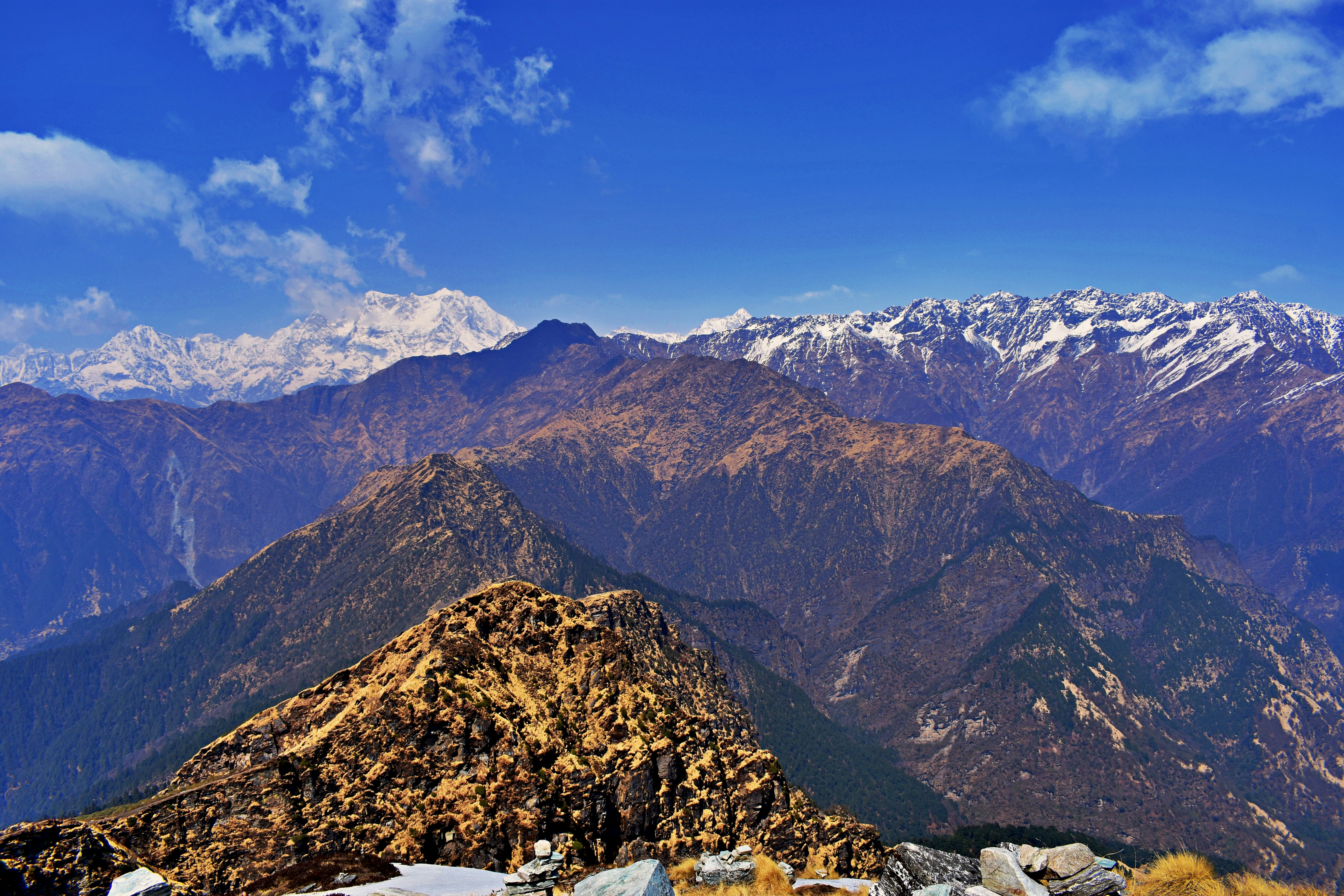 Mountain peaks with snow-capped summits under a vibrant blue sky.