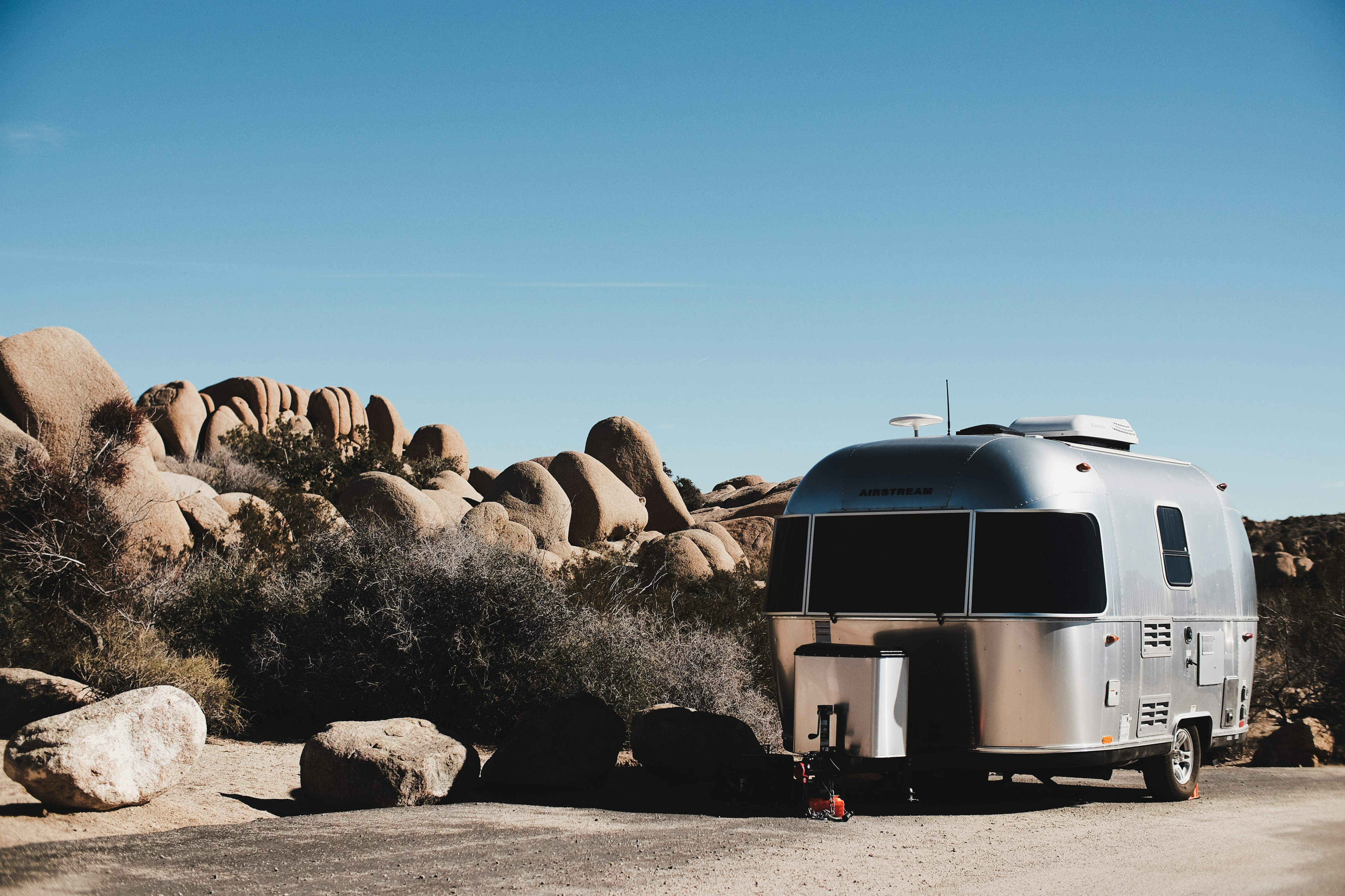 Gray travel trailer parked beside brown rocks photo – Free Blue Image ...