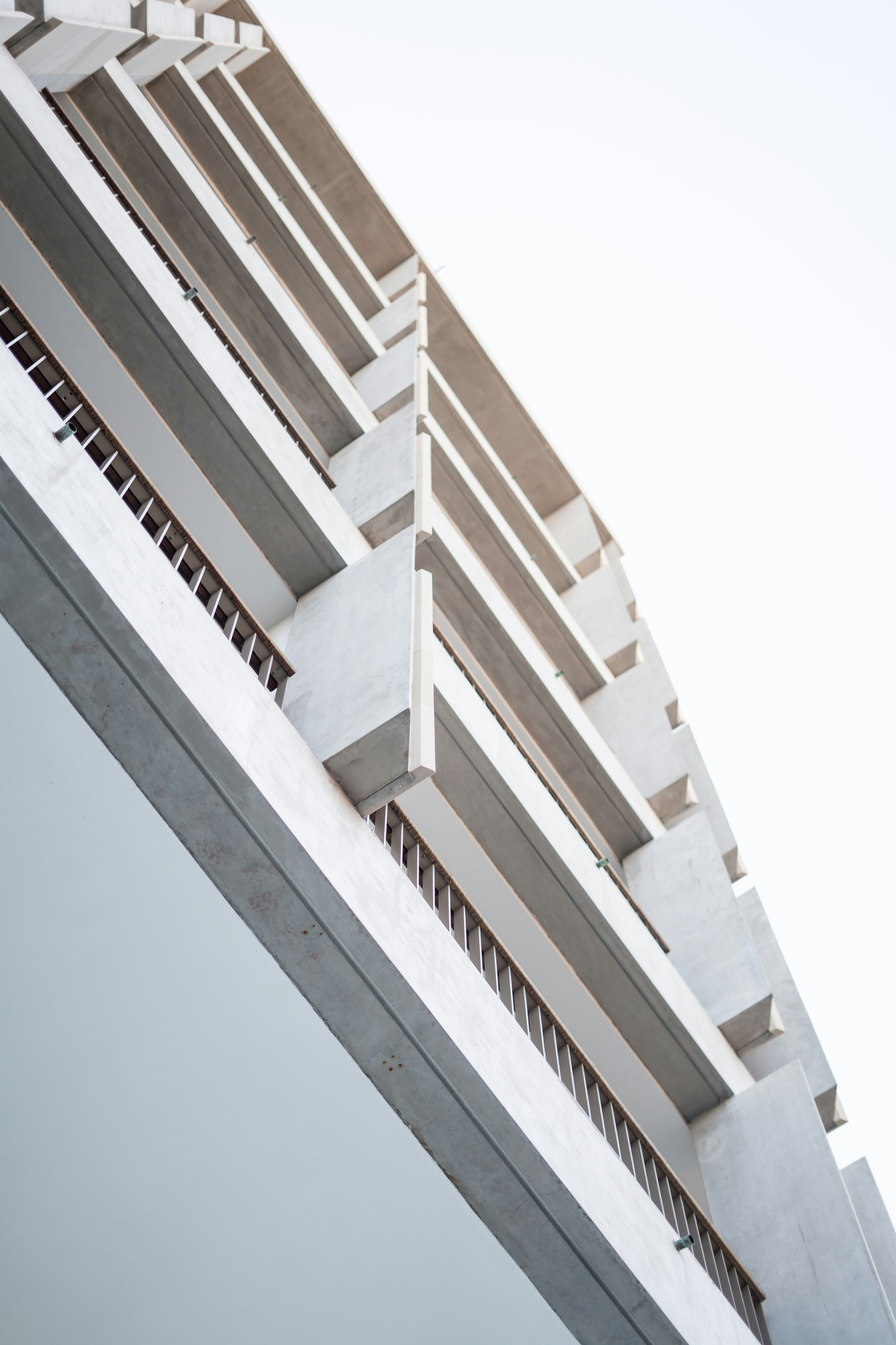 Abstract view of a modern building's concrete facade with balconies and a clear sky backdrop.