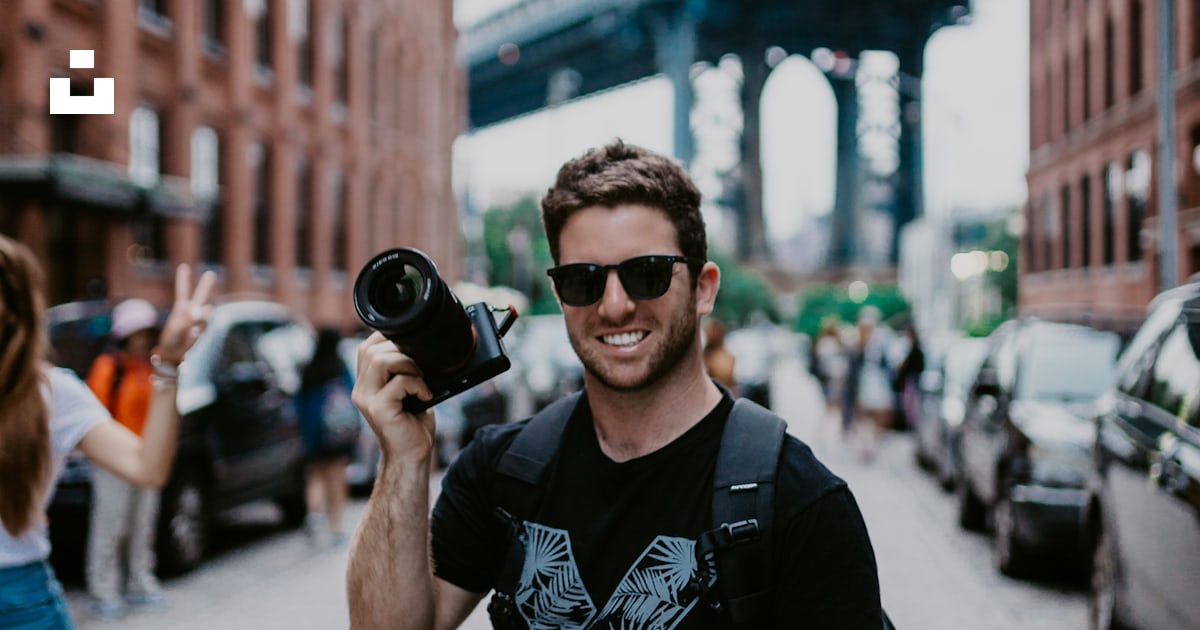 Hombre Sonriente Sosteniendo Una Cámara Dslr Que Lleva Una Mochila