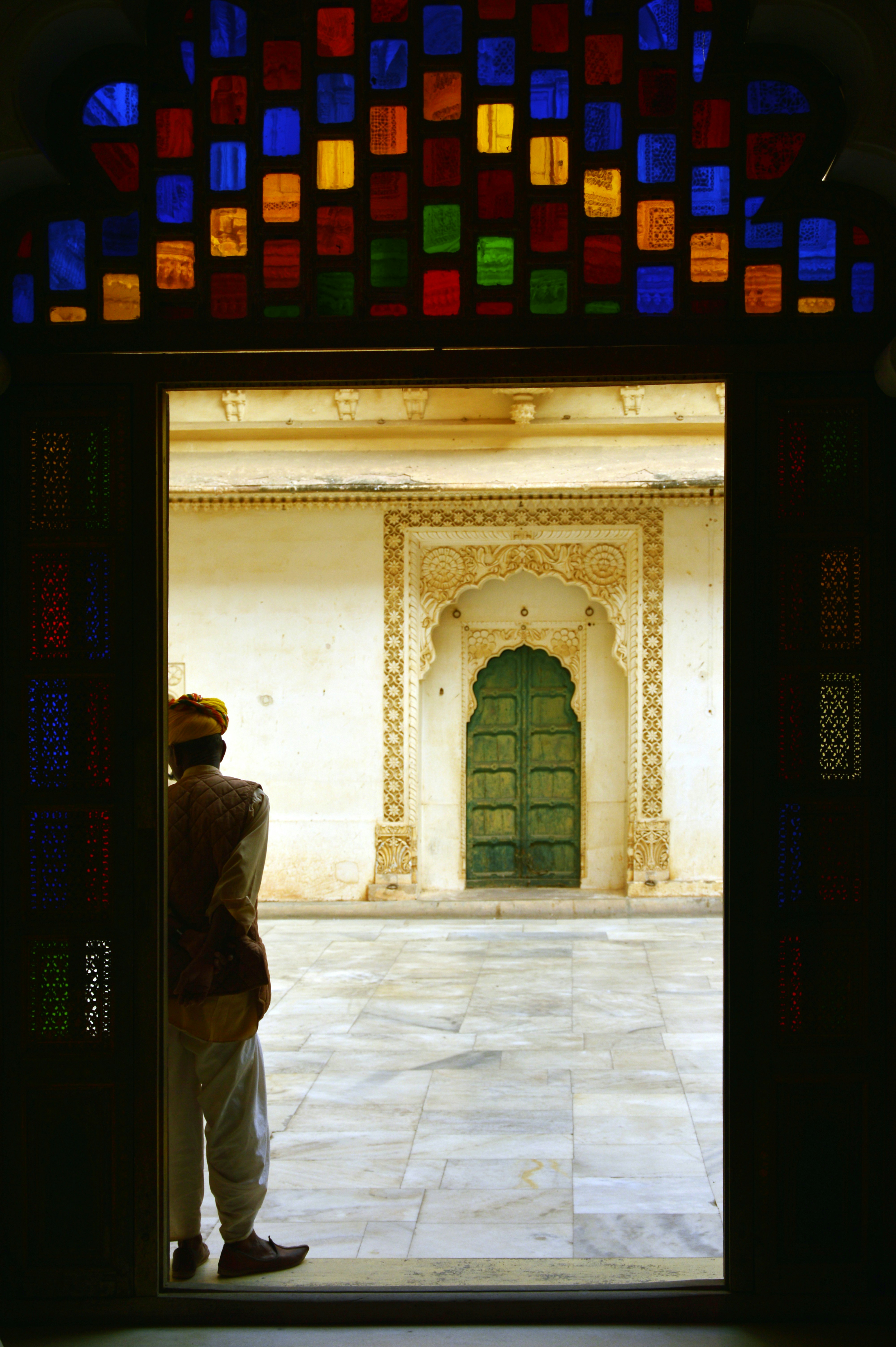 Threshold of Color: Marble Courtyard Framed by a Green Door under a Mosaic Arch