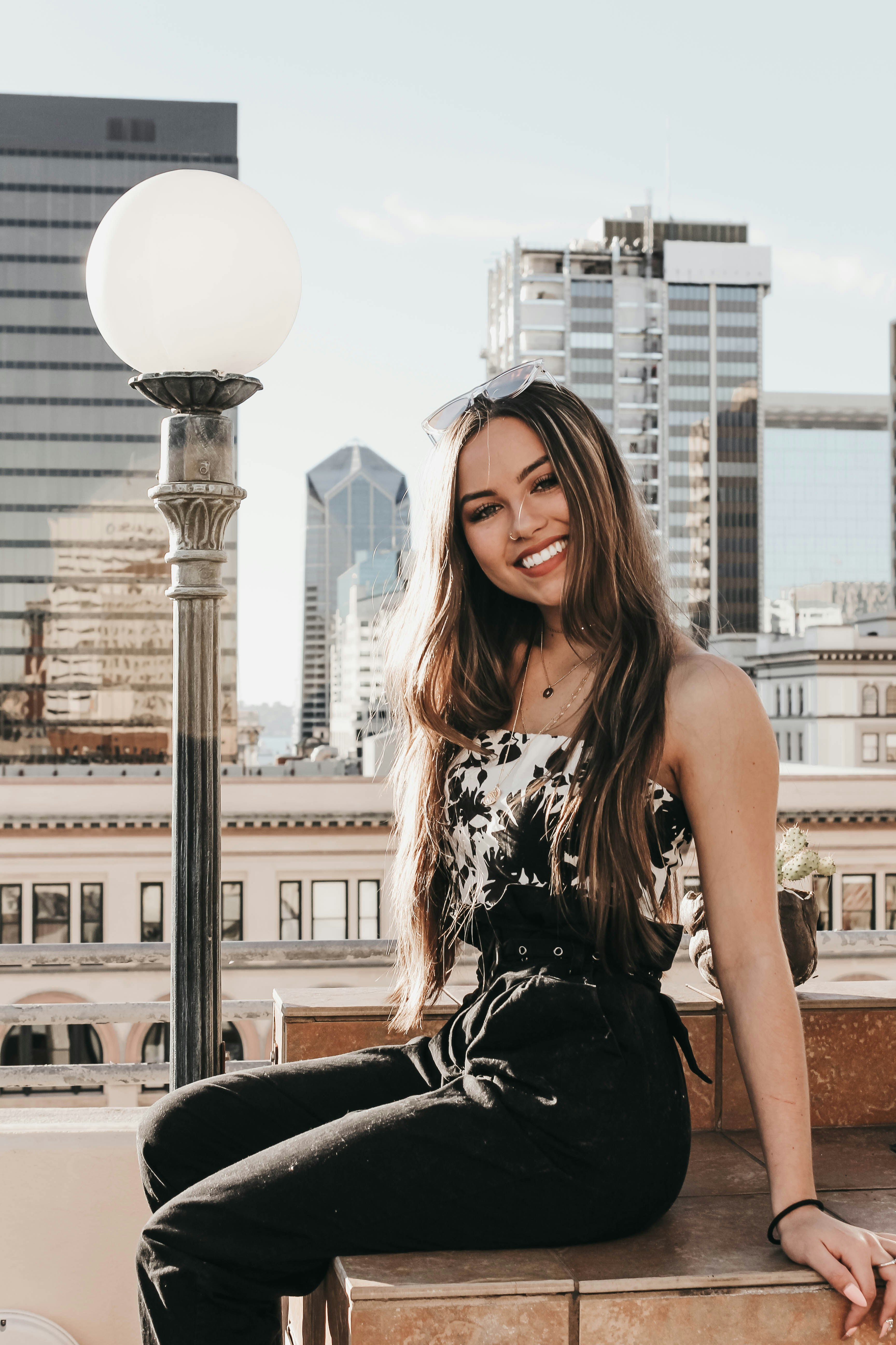 Woman in floral strapless top smiling against a city skyline backdrop.