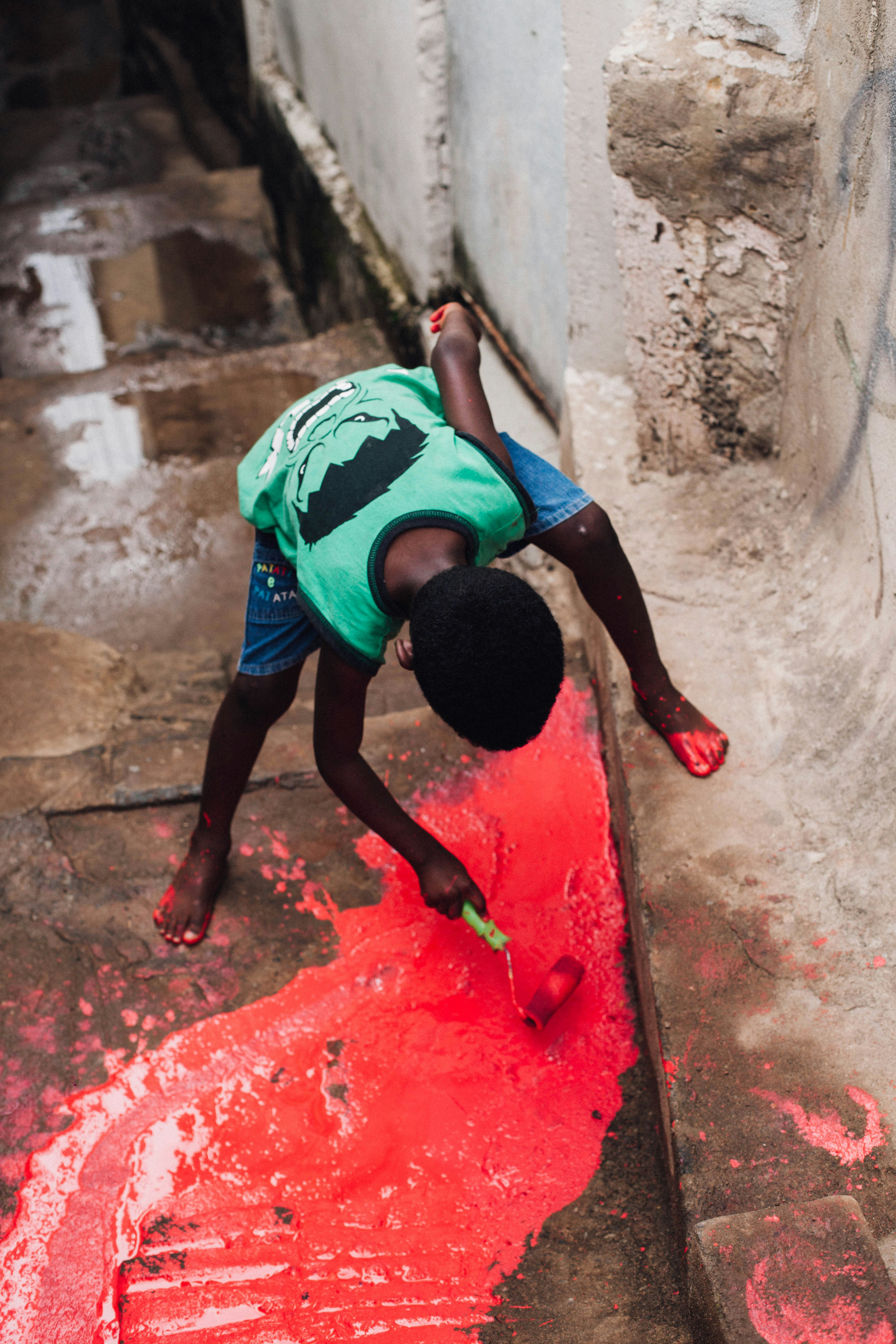 Child Painting a Narrow Alley with Bright Red Paint
