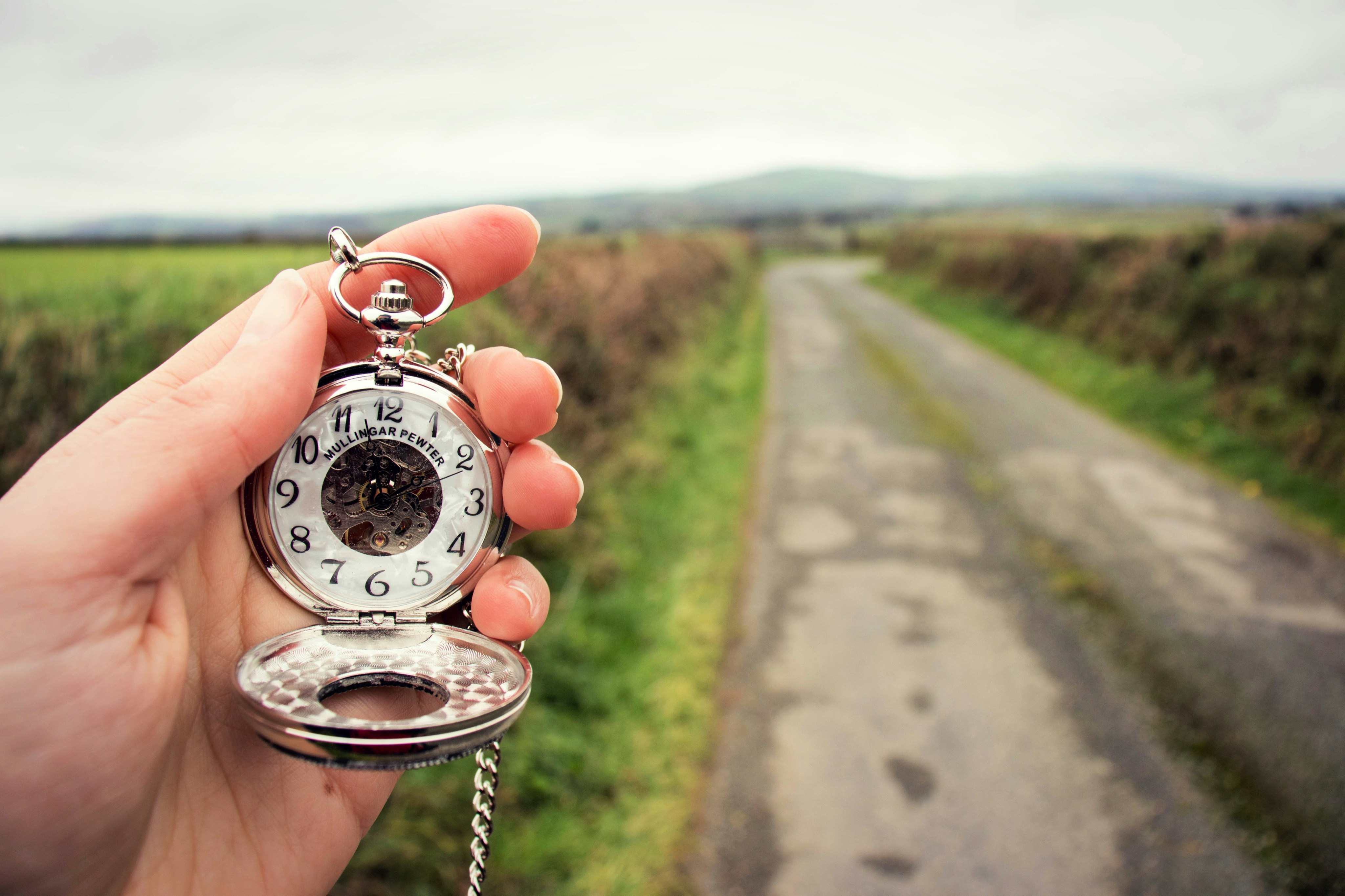 person holding silver-colored pocket watch