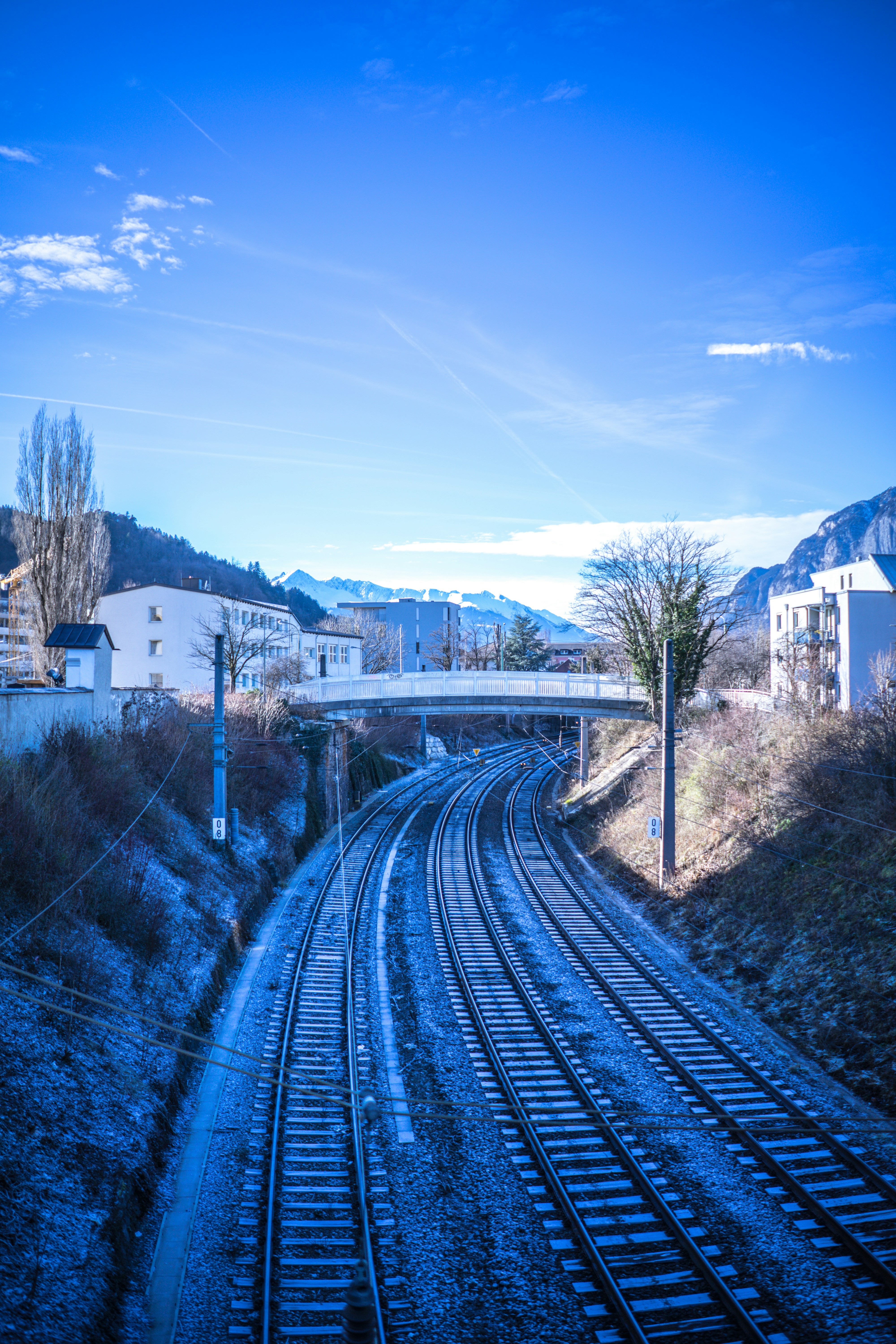 Converging Rails through an Alpine Valley under a Crisp Blue Sky