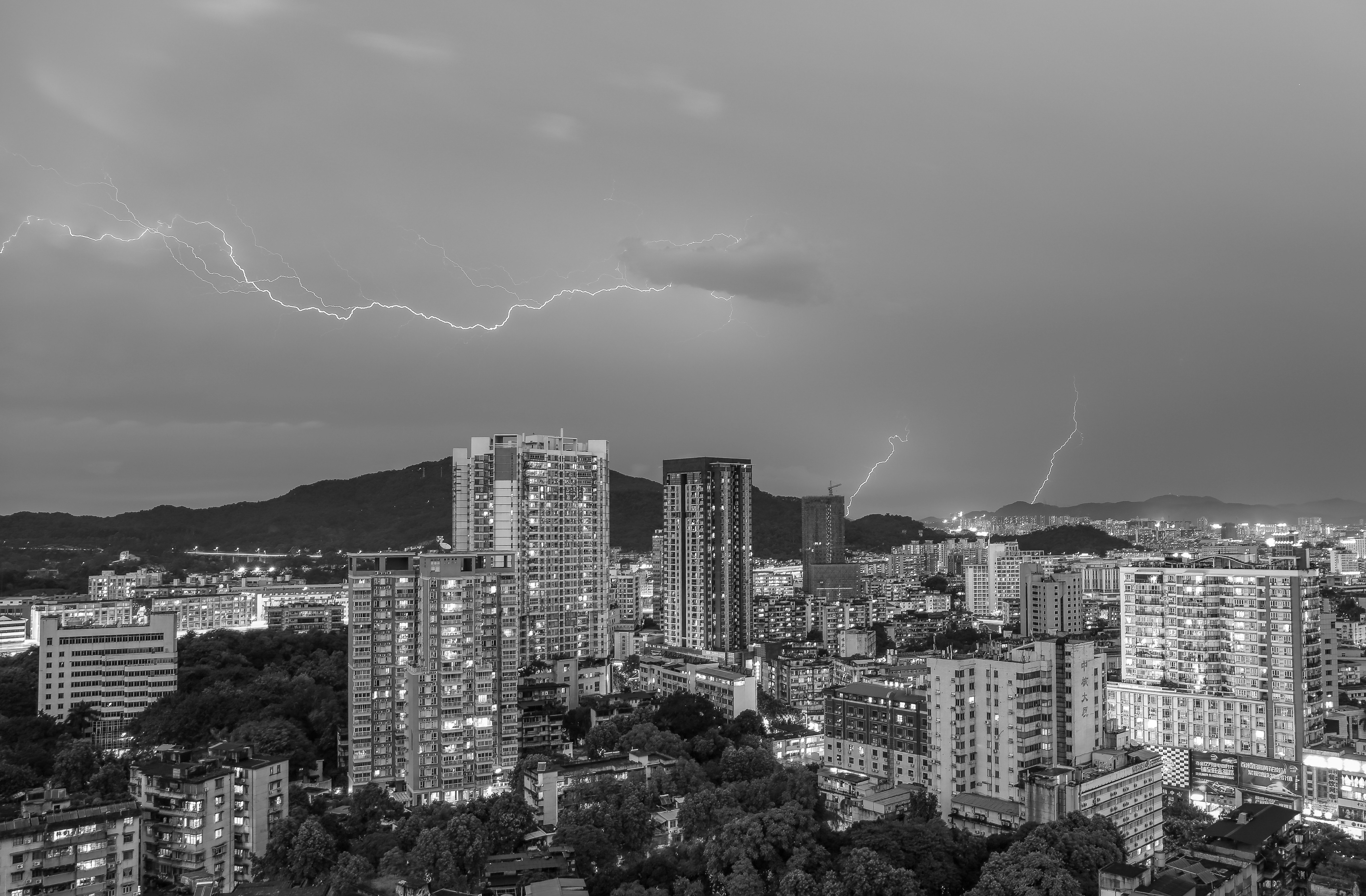Dramatic lightning strikes illuminate a sprawling urban landscape under a moody sky, showcasing the contrast between nature's fury and human architecture.