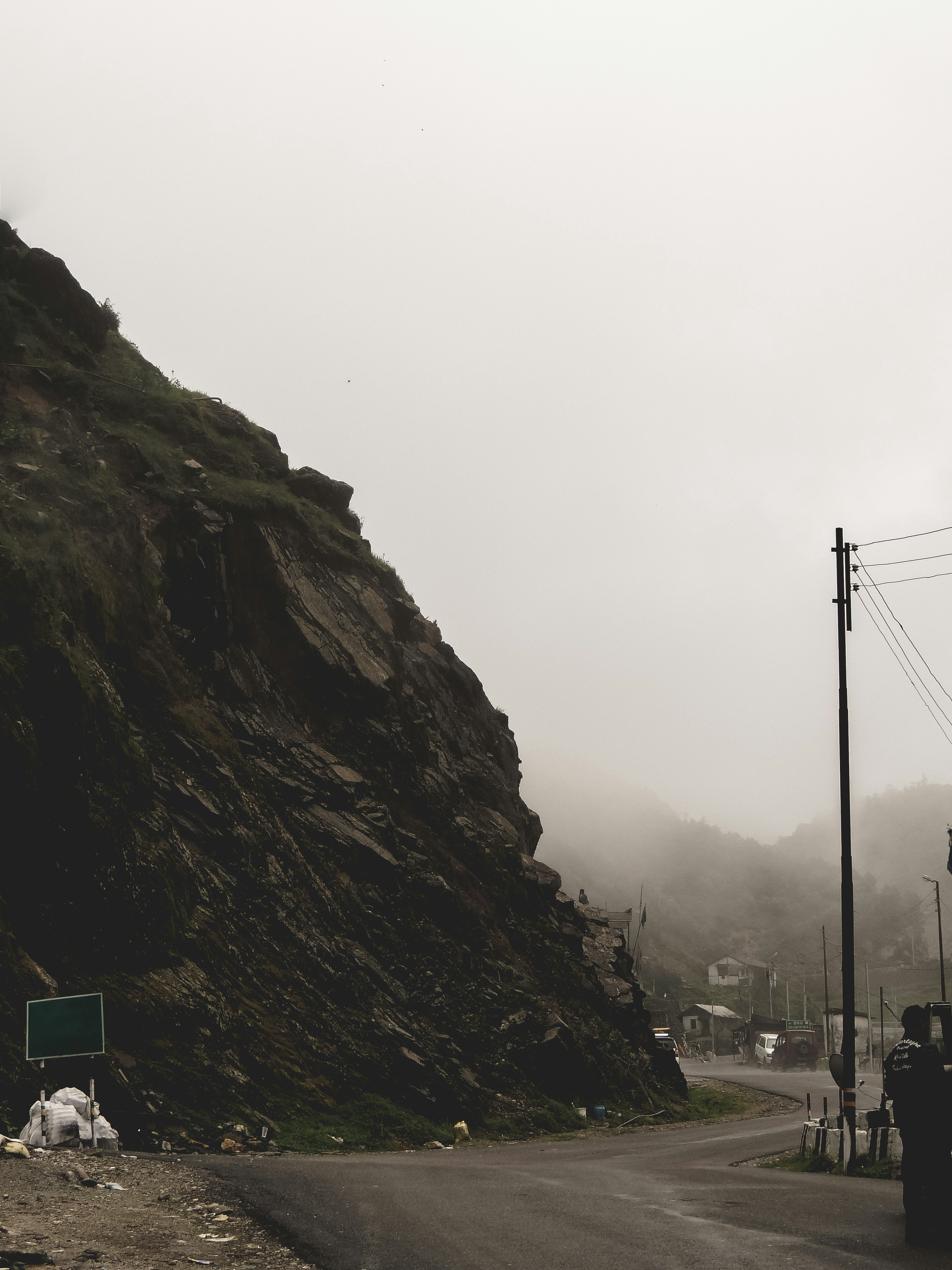 Fog over the coastal road: cliffside, utility poles, and a winding descent