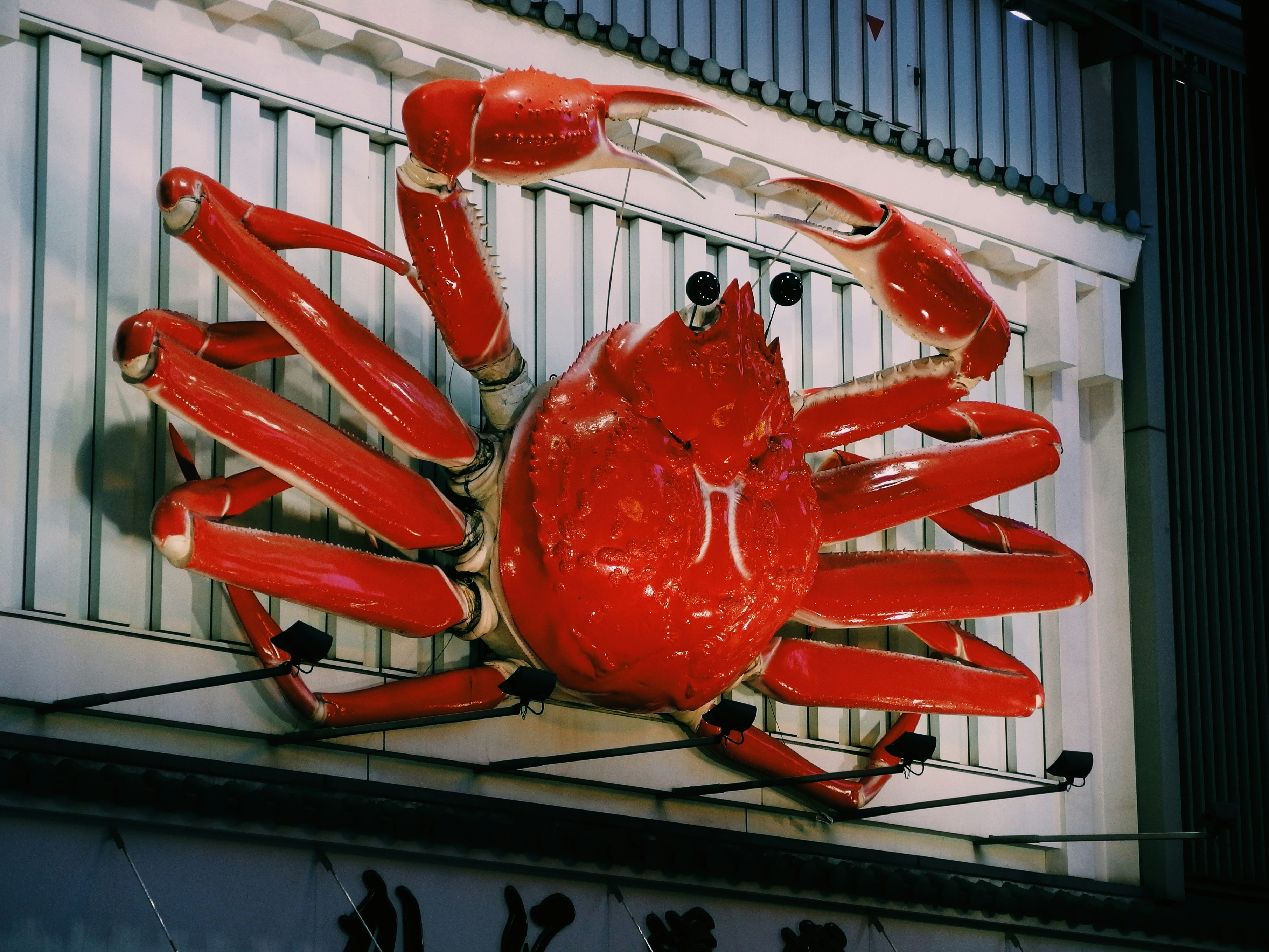 Vibrant red crab sculpture prominently displayed on a restaurant facade, inviting diners with its oversized presence.