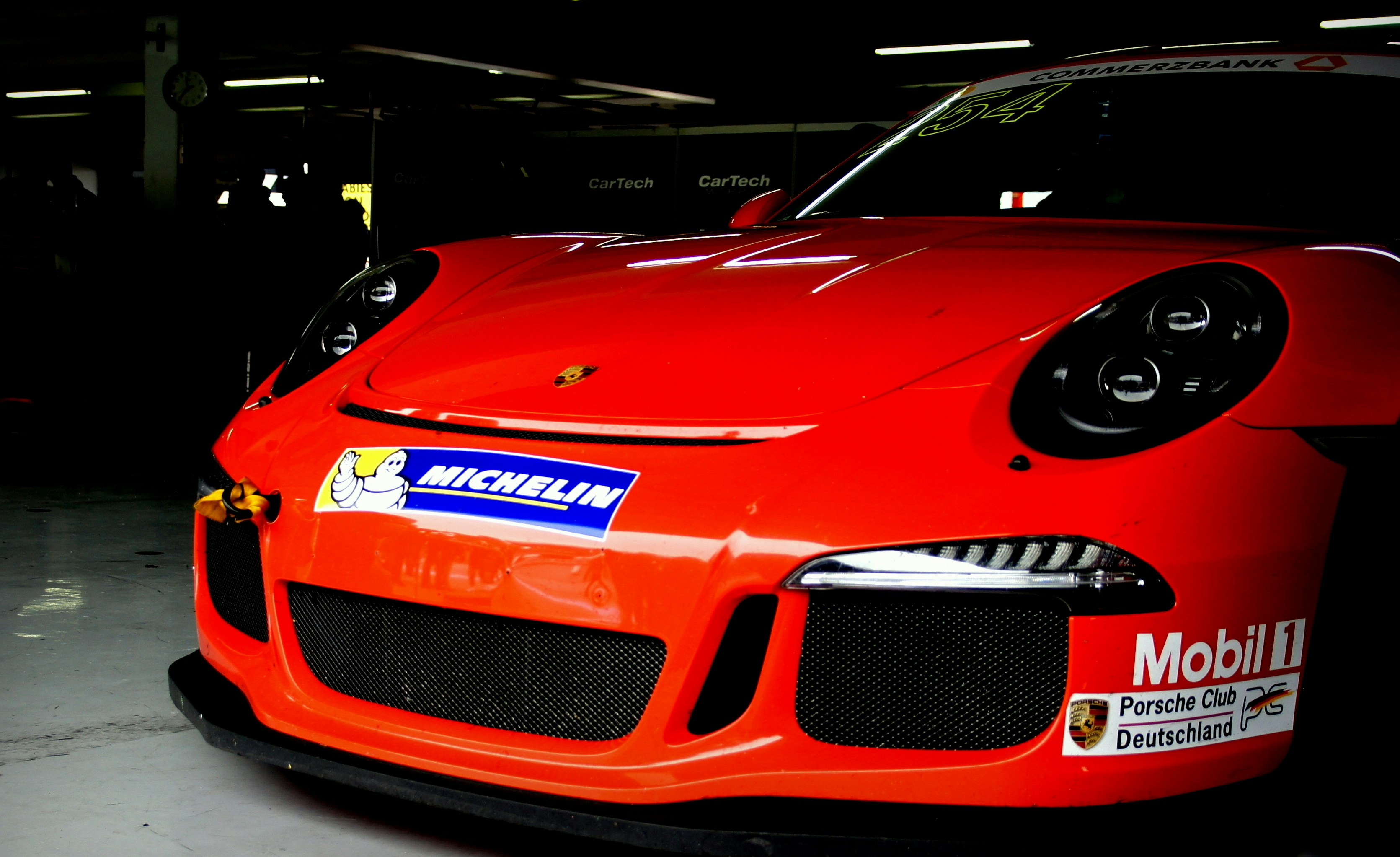 Red sports car in a dimly lit garage, showcasing aerodynamic design and sleek contours.