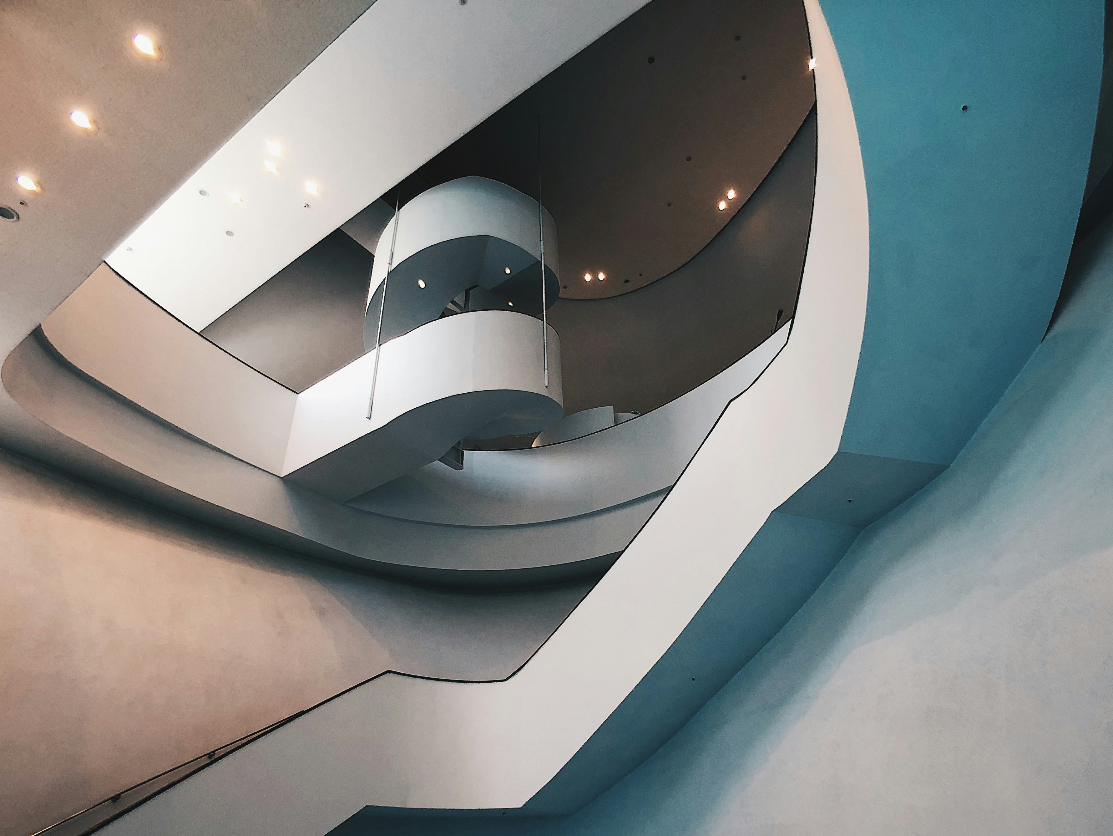 Curved architectural forms of a modern spiral staircase against a sky blue backdrop.