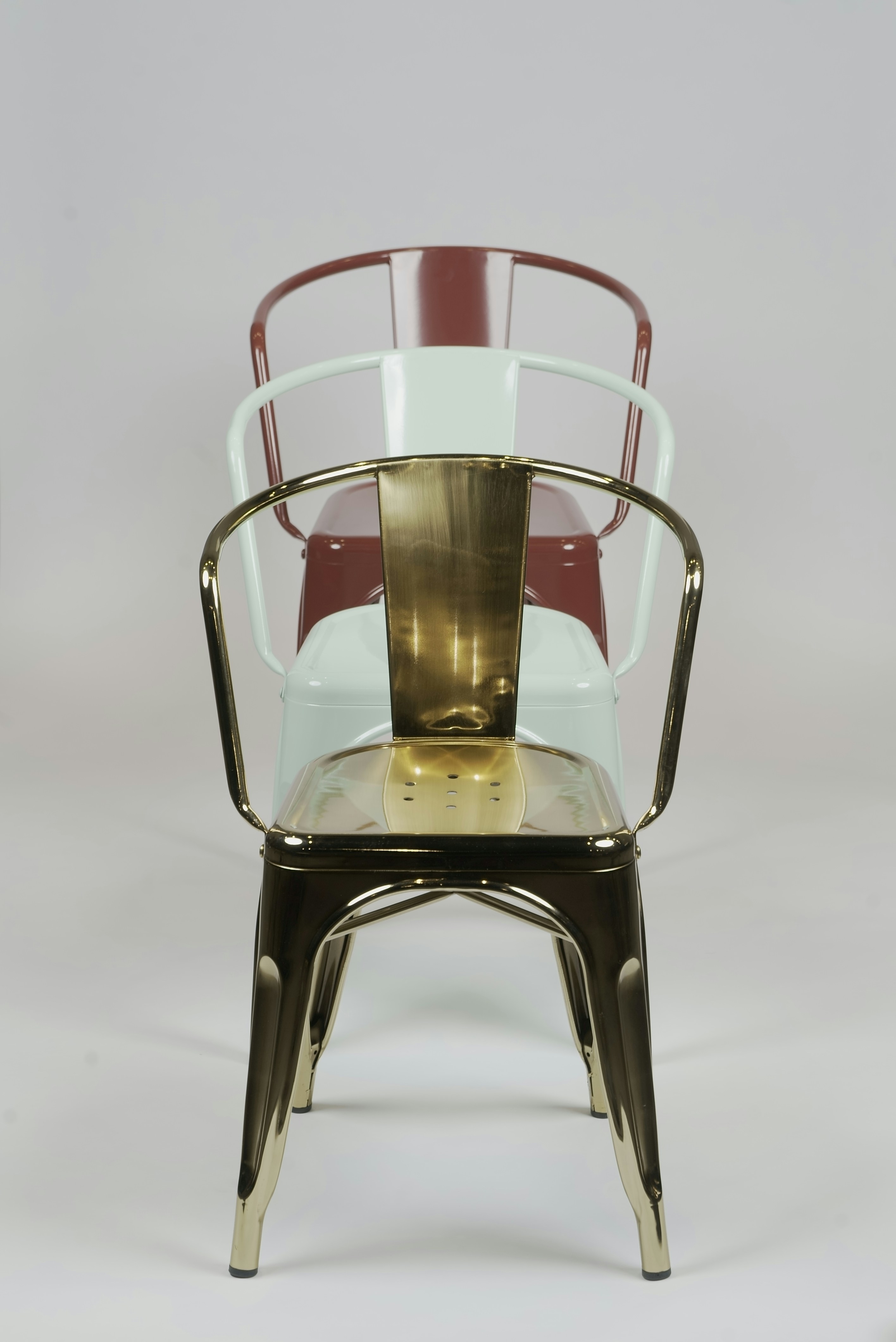 Chromatic Stack: a quartet of glossy metal chairs aligned in mirrored light
