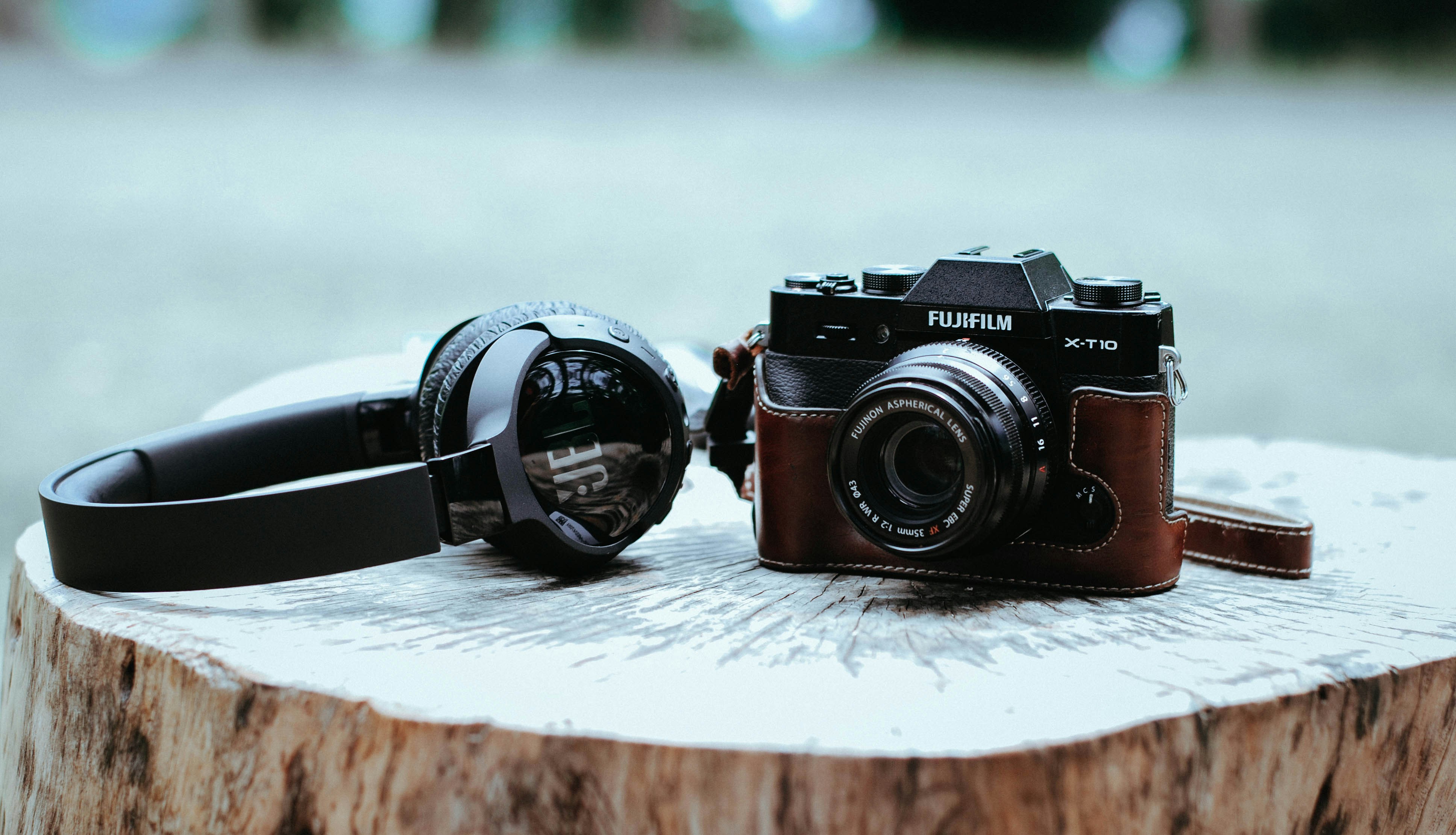 On a Weathered Log: Fuji X-T10 with Leather Grip Resting Beside Headphones