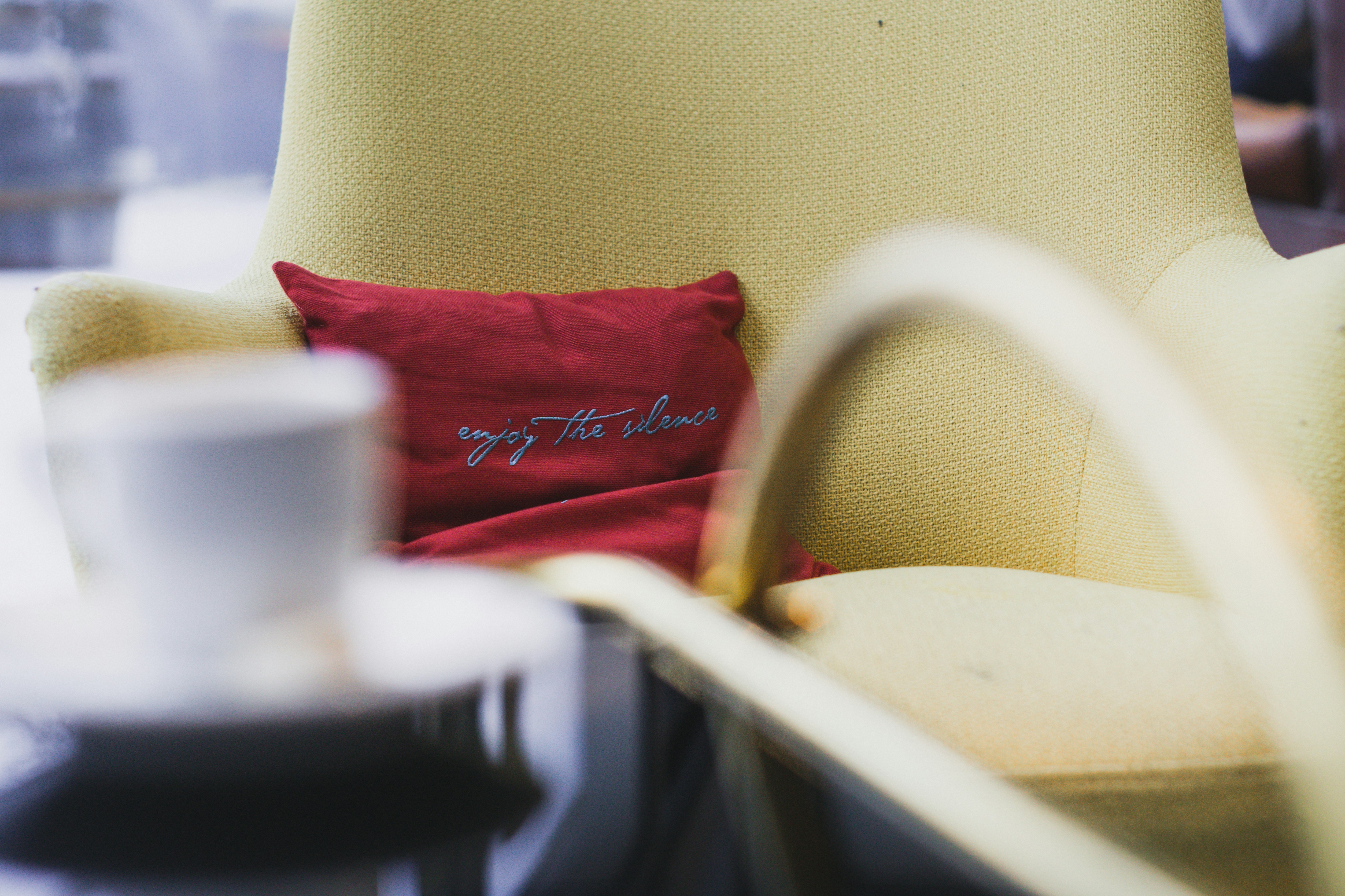 Cozy corner with a red quote pillow on a pale yellow chair