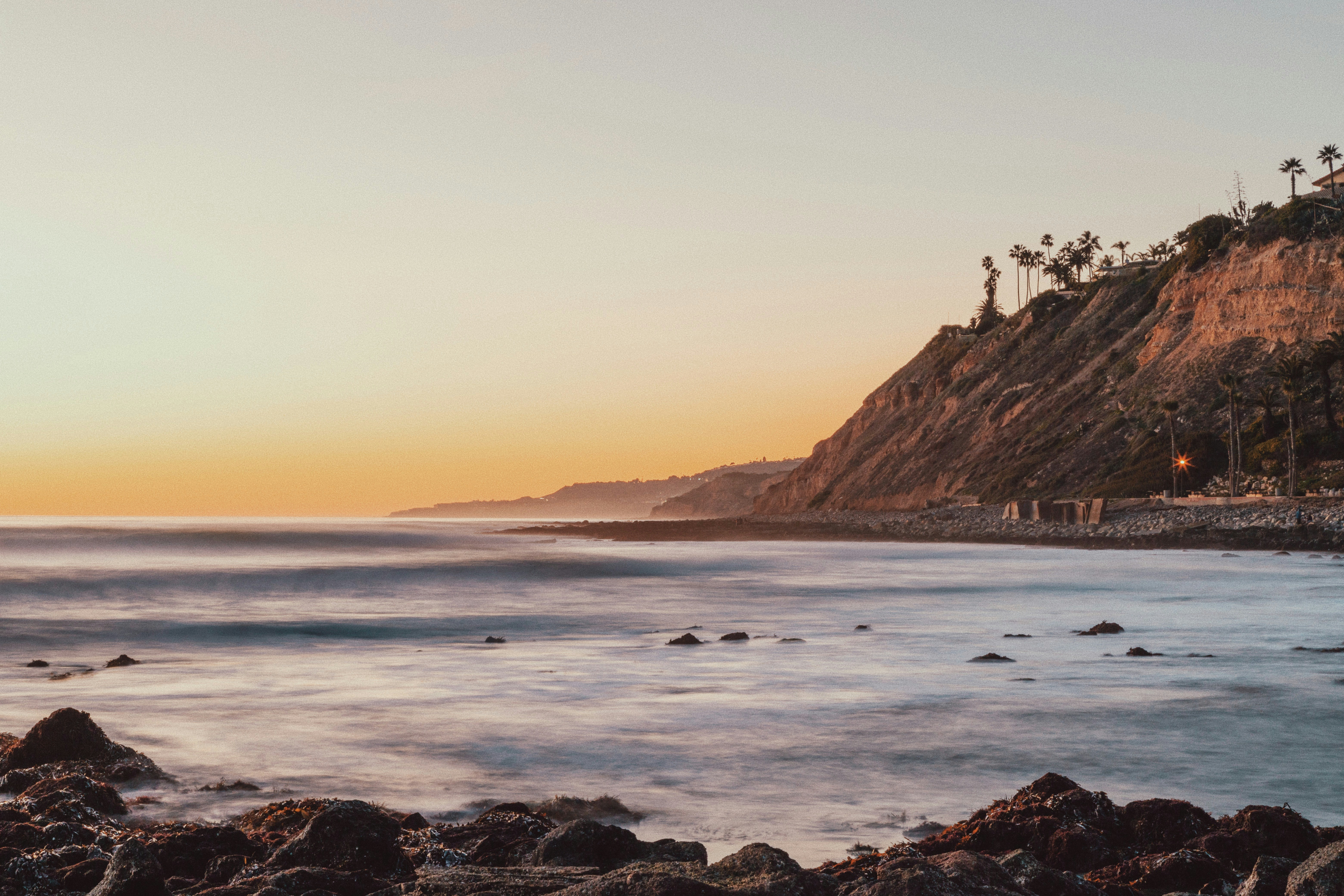 Calm sea near island under white sky photo – Free Surfing Image on Unsplash