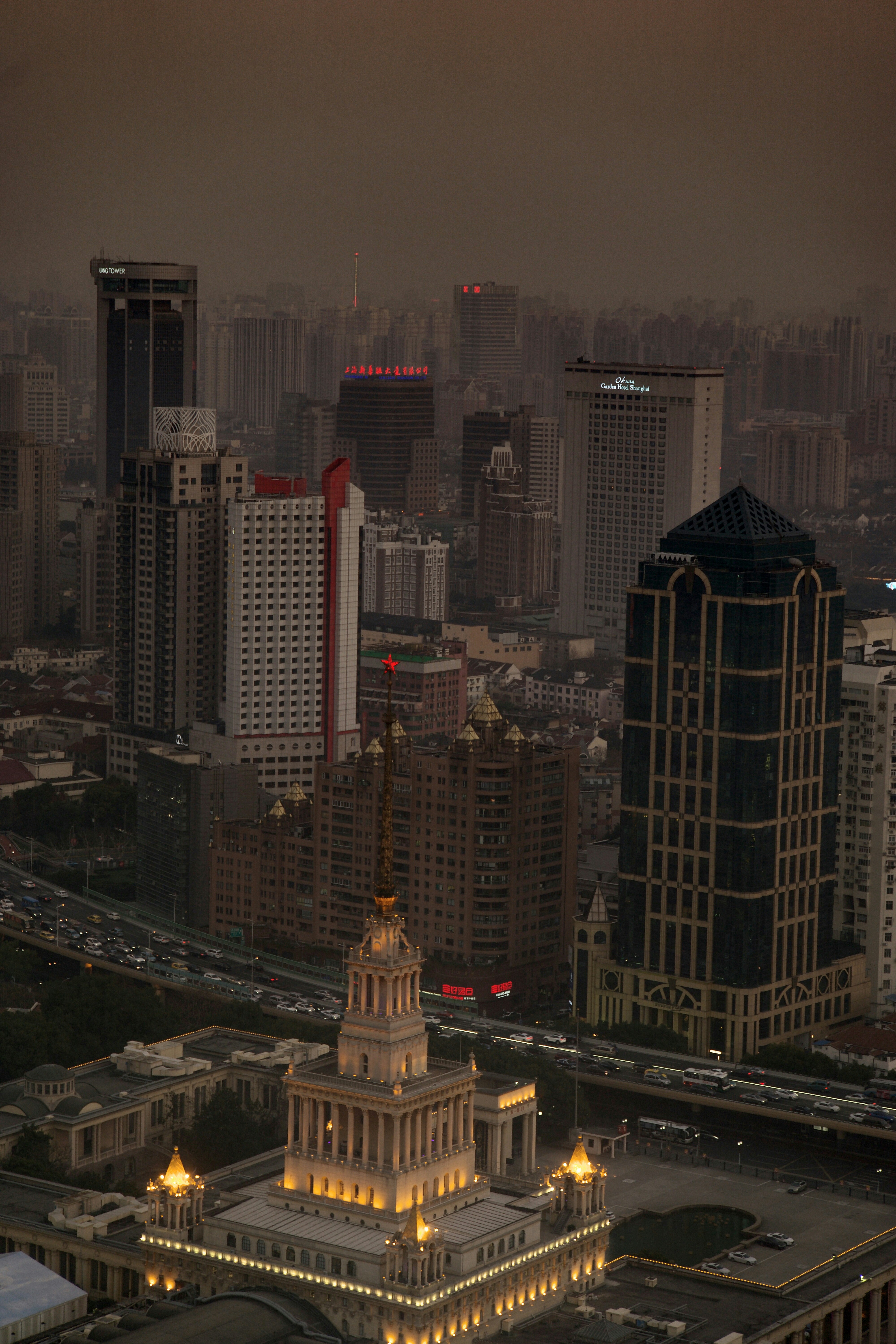 Illuminated historic building contrasts with modern skyscrapers in a bustling cityscape at dusk.