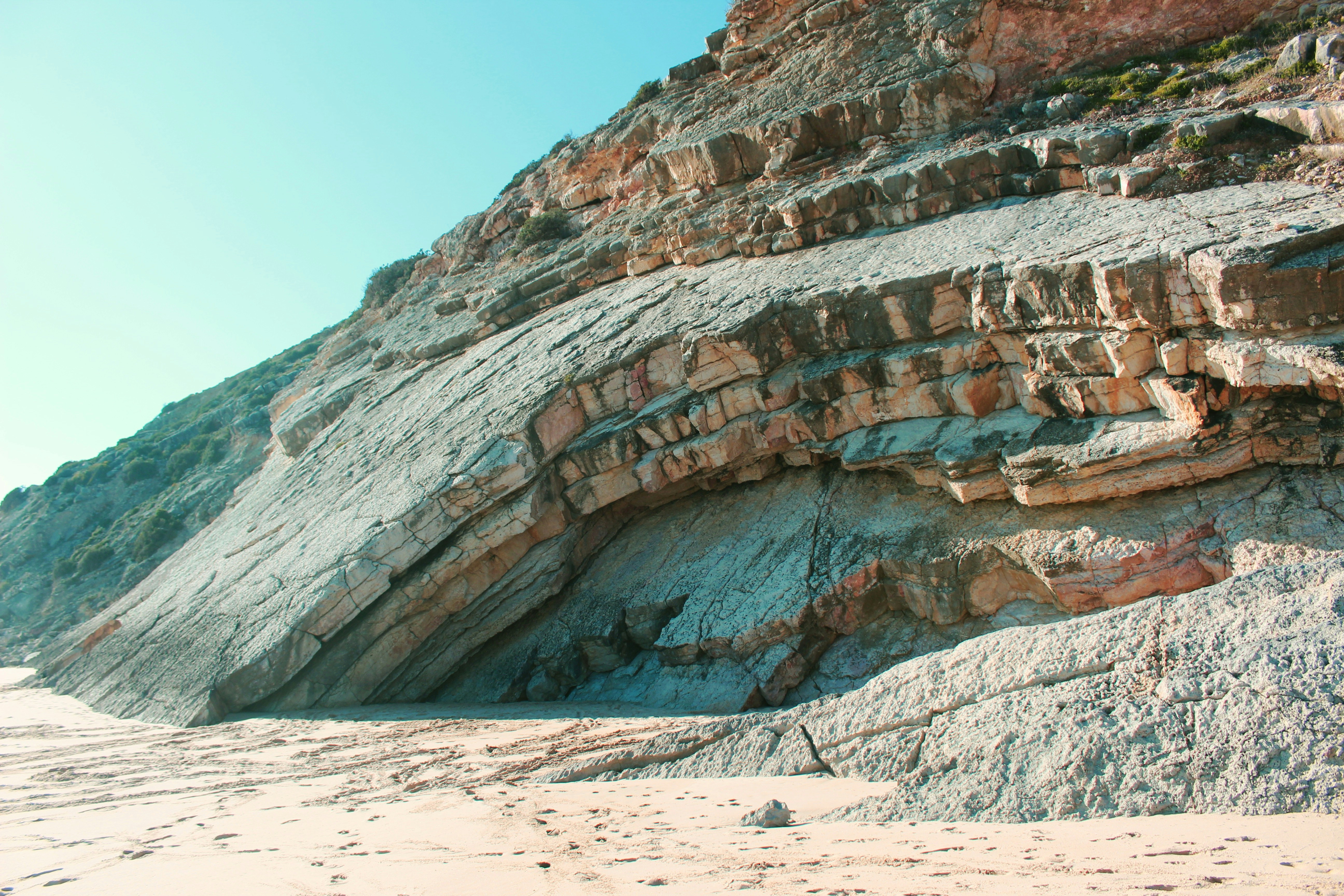 Intricate layers of rock formations on a sunlit beach, showcasing the natural erosion and geological history of the area.
