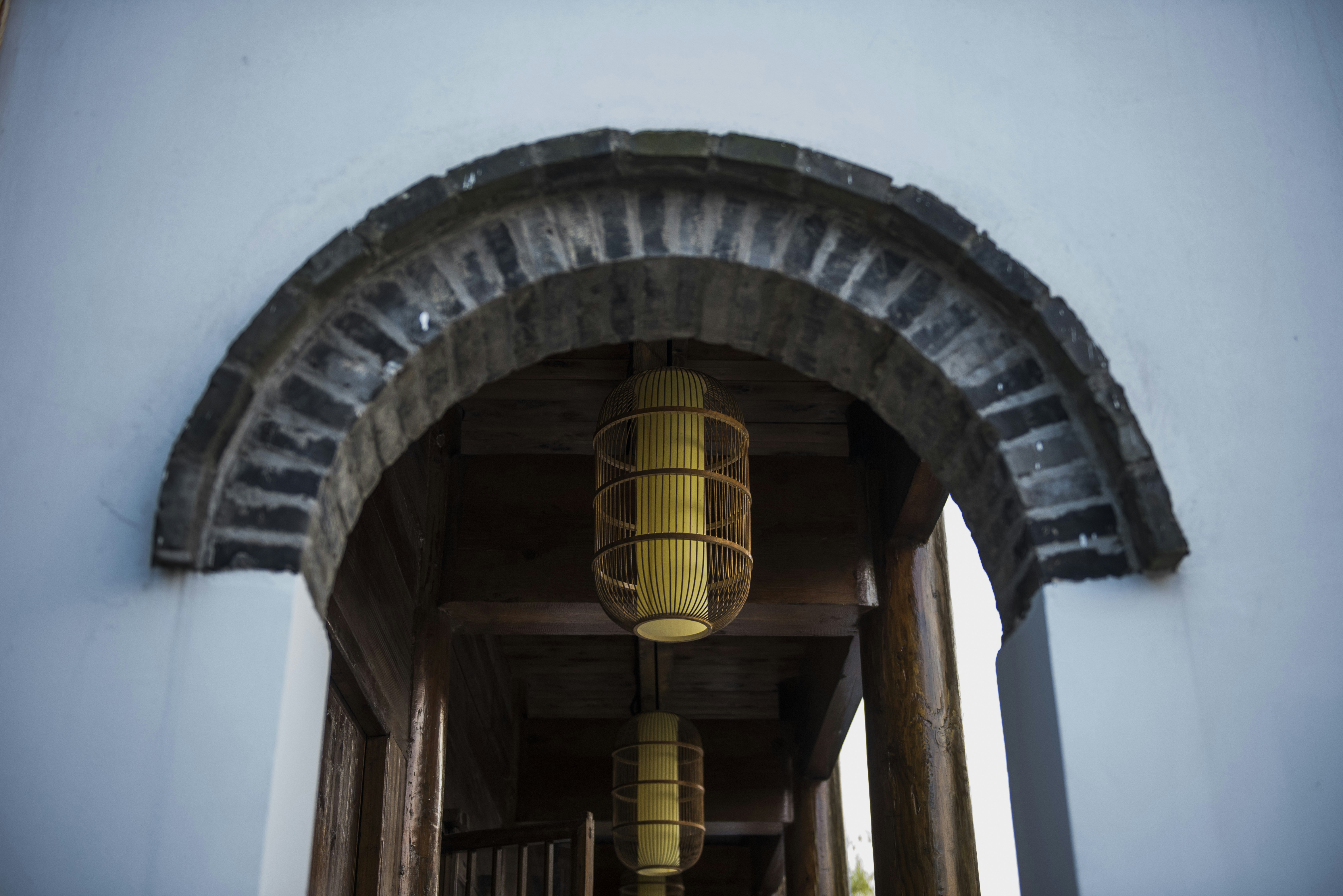Archway Lanterns: Midday Light Through Wooden Corridor