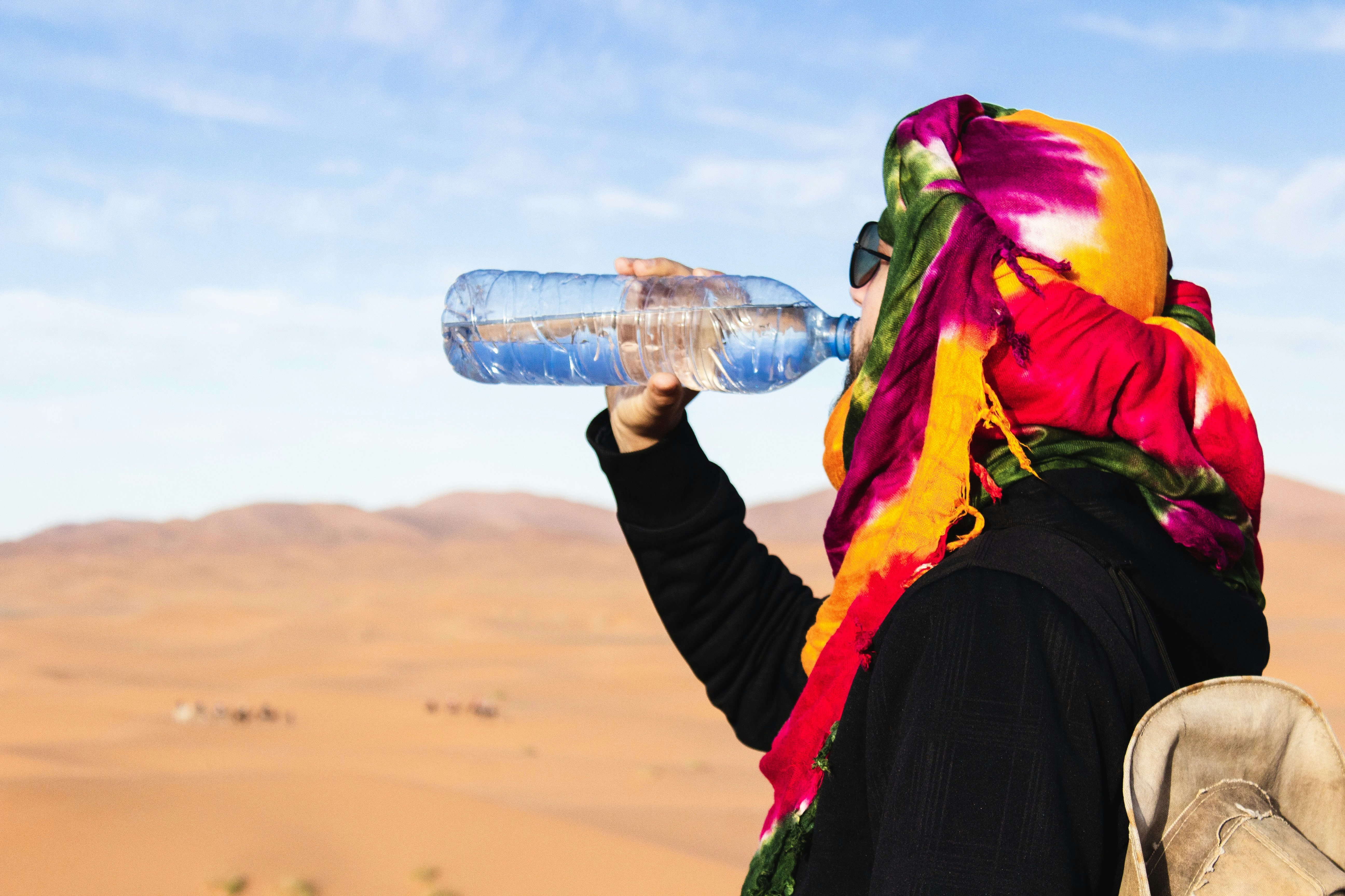 Desert Sun and Hydrated Resolve: A Woman in Colorful Turban Sips from a Water Bottle