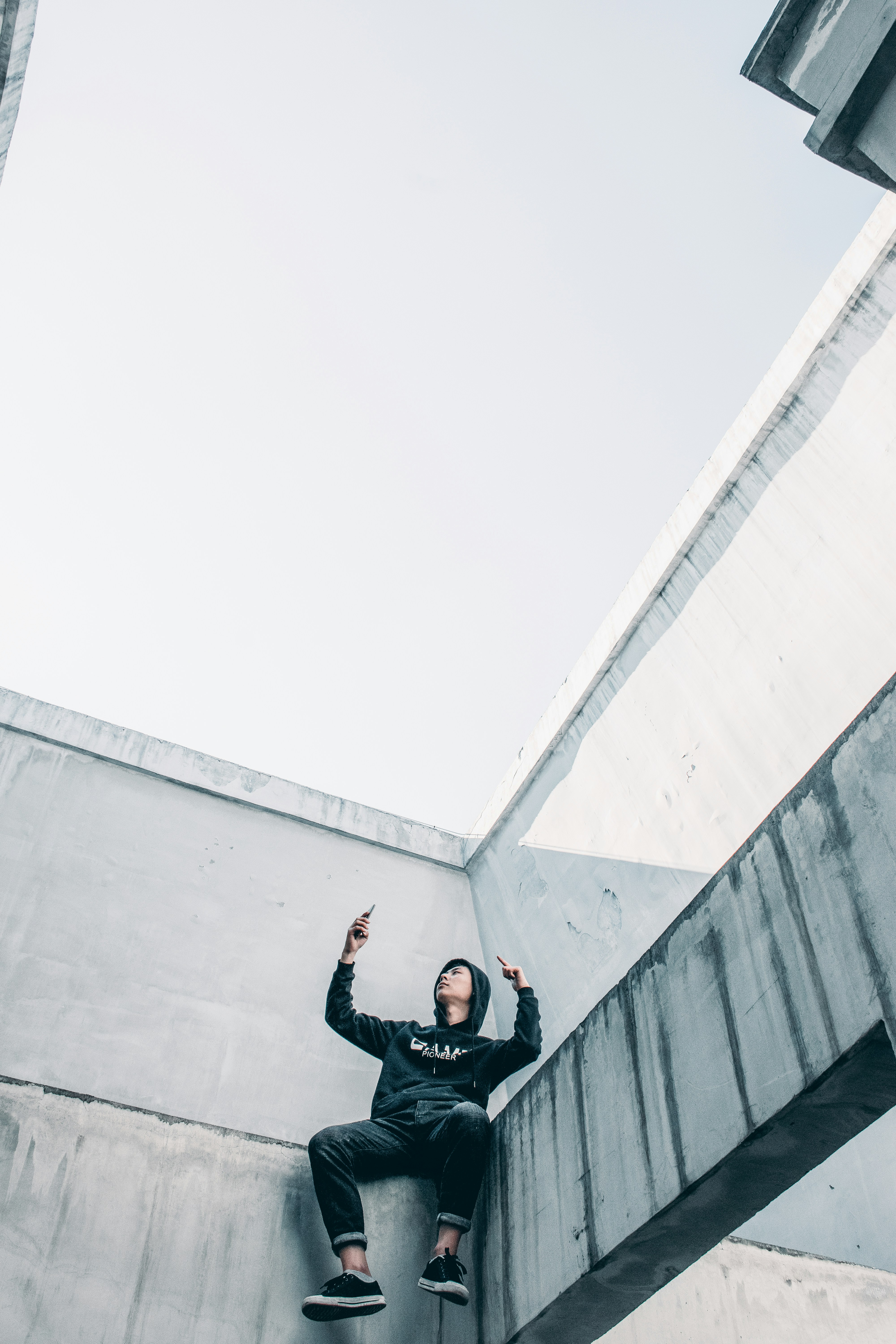Man sitting by ledge of building during daytime photo – Free White ...