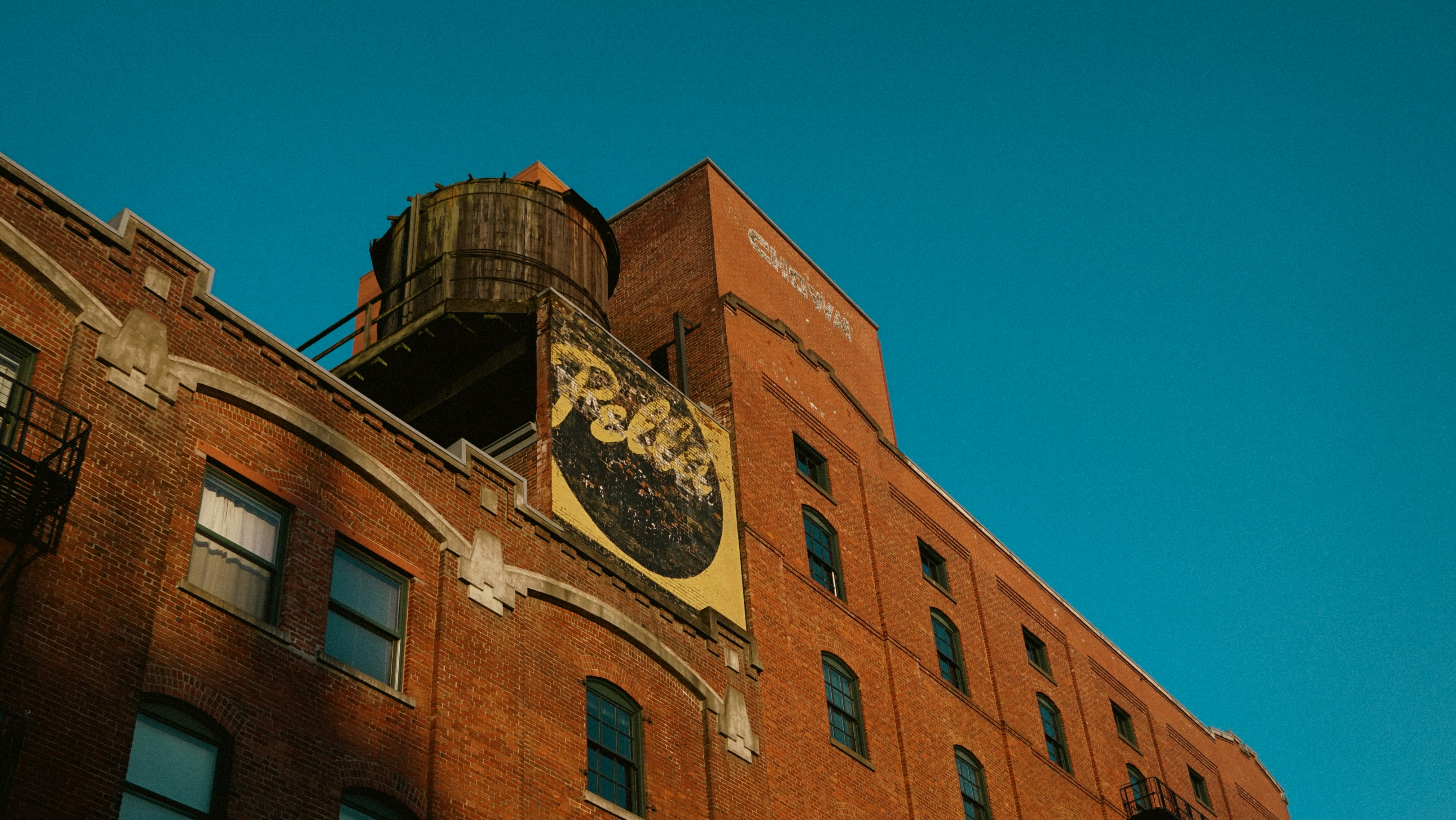 Circular Mural on a Red Brick Facade Beneath a Pristine Blue Sky