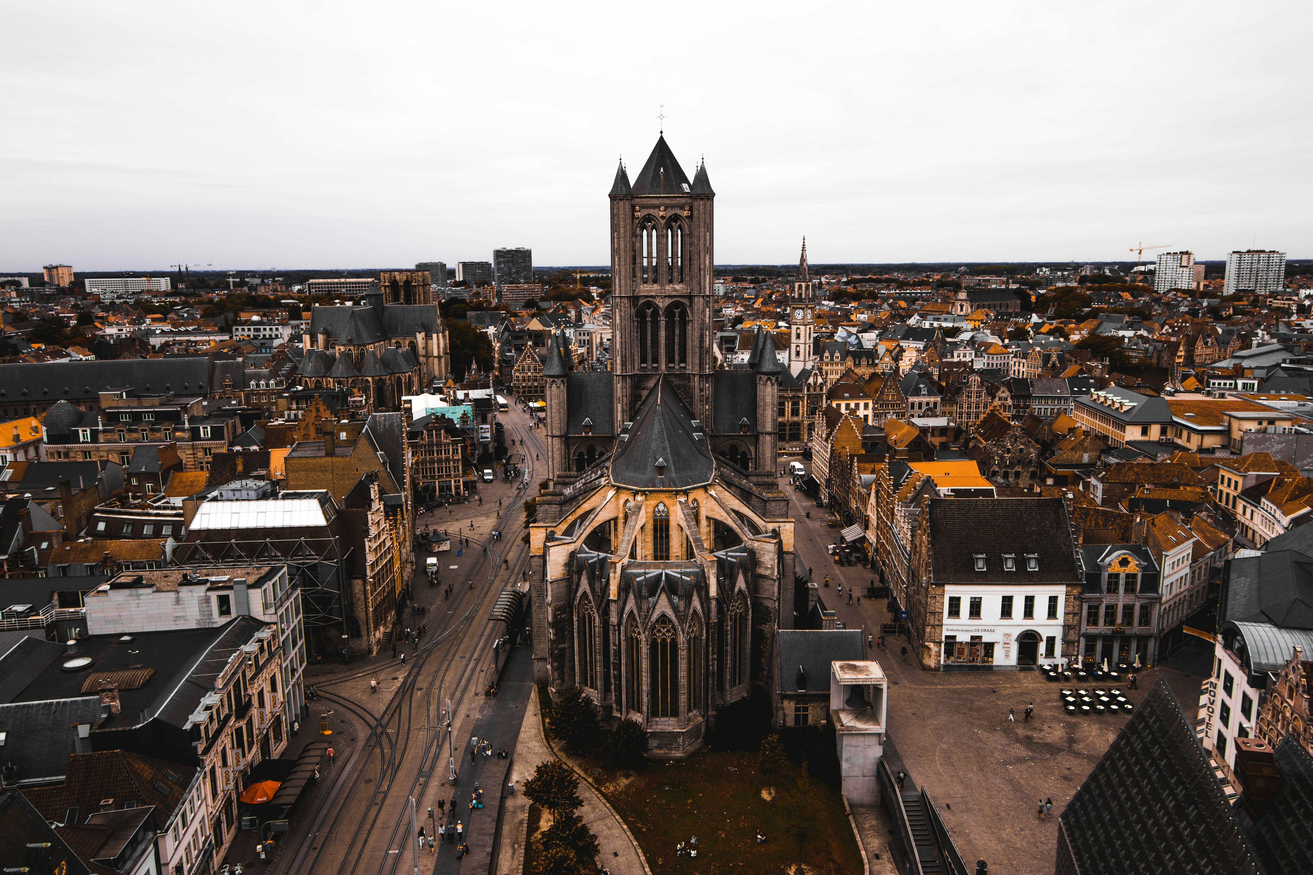 Gothic cathedral towers over a bustling cityscape under an overcast sky.