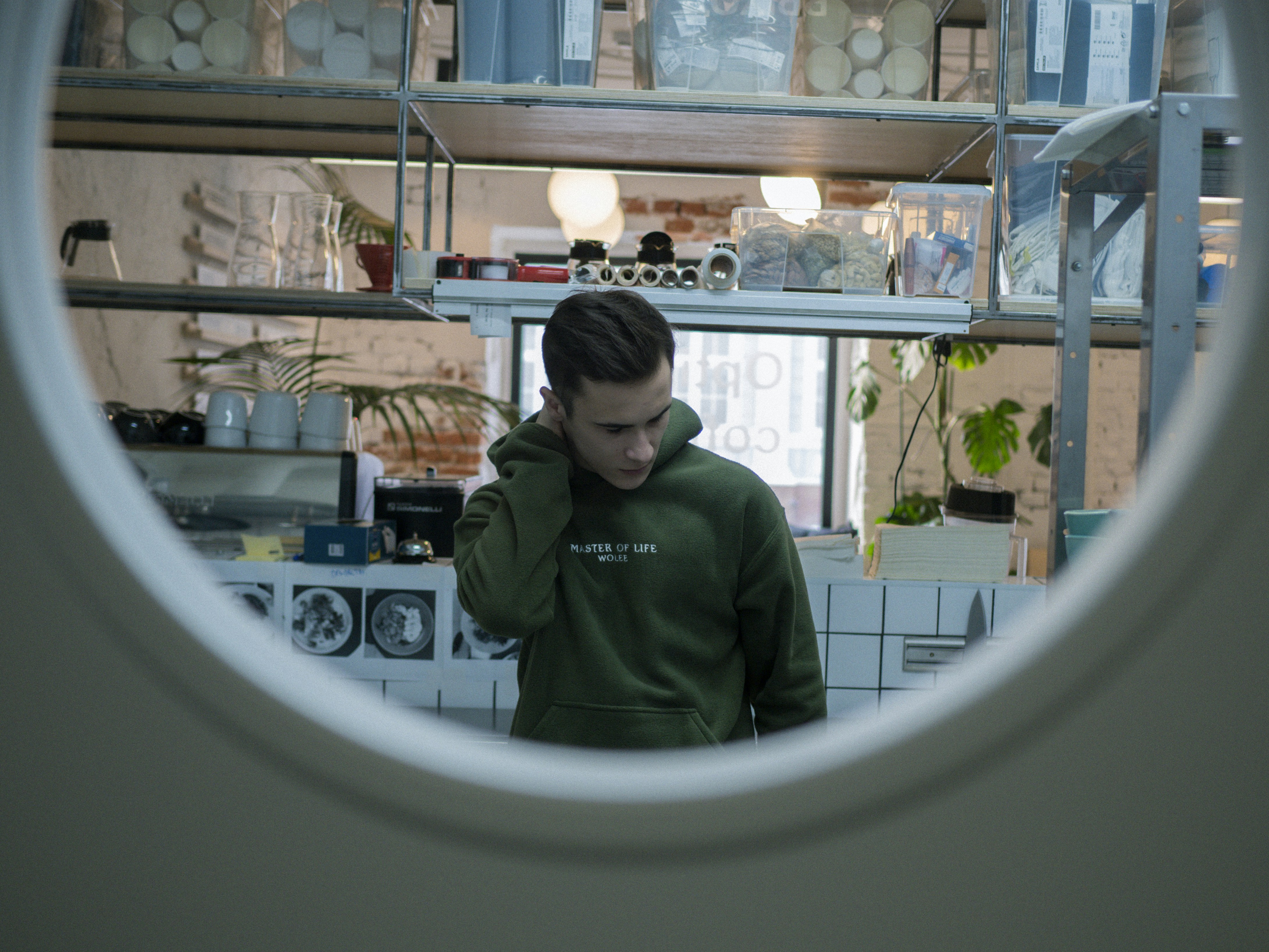 man in green jacket holding his nape view from behind door