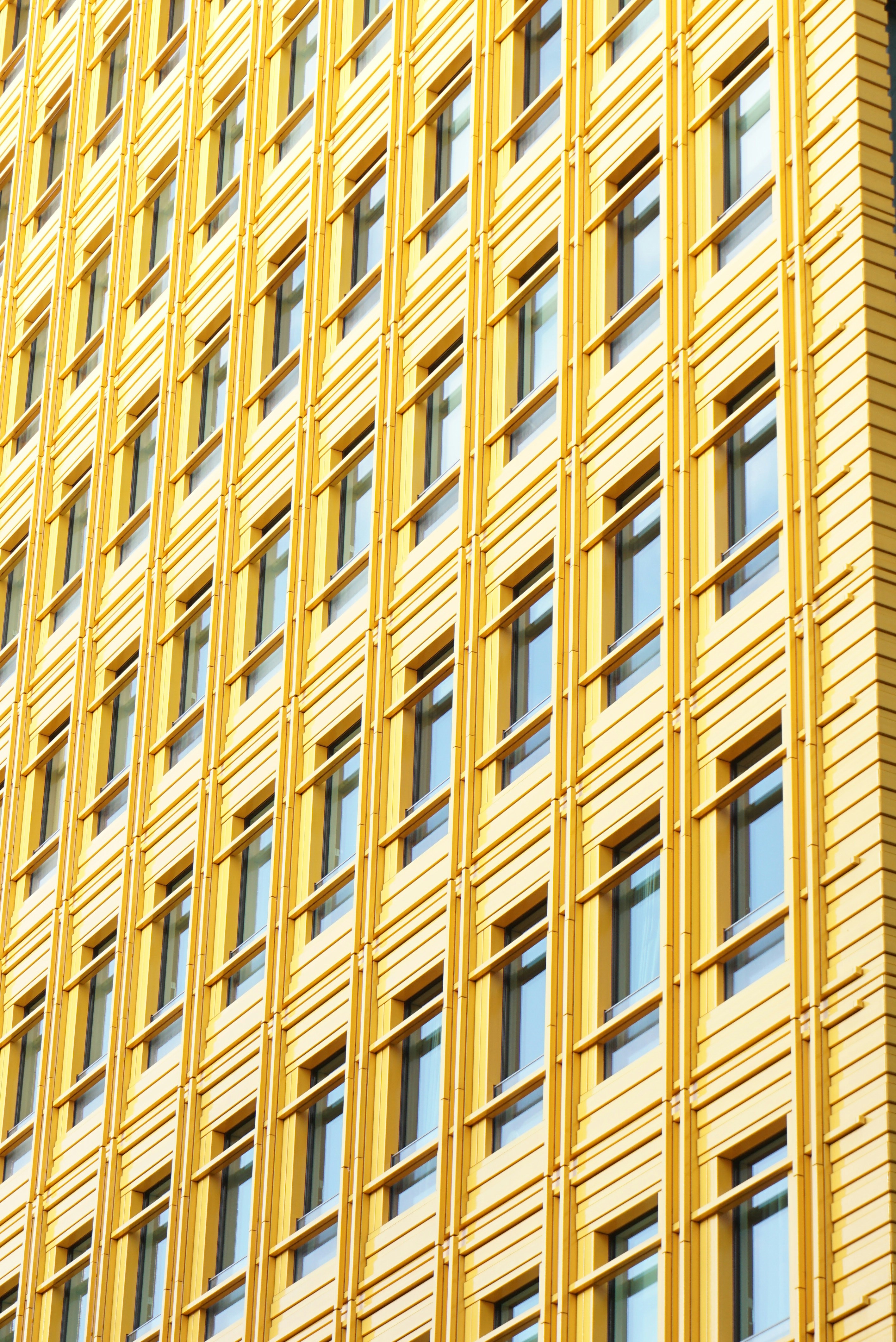 Close-up of a vibrant yellow building facade showcasing a rhythmic pattern of windows and lines.