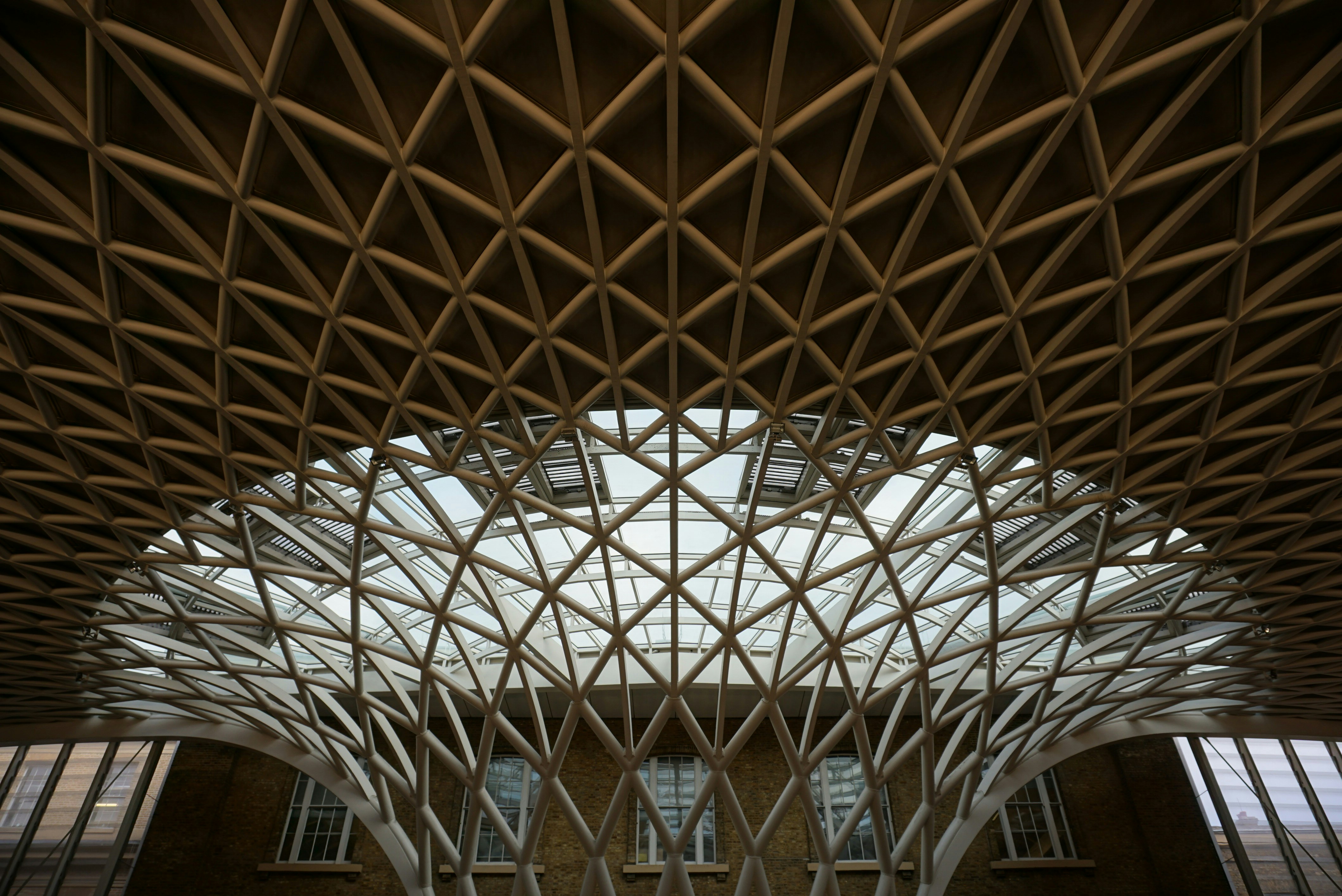 Intricate latticework of a modern architectural ceiling, showcasing geometric patterns and natural light filtering through. The design emphasizes the blend of structure and aesthetics.