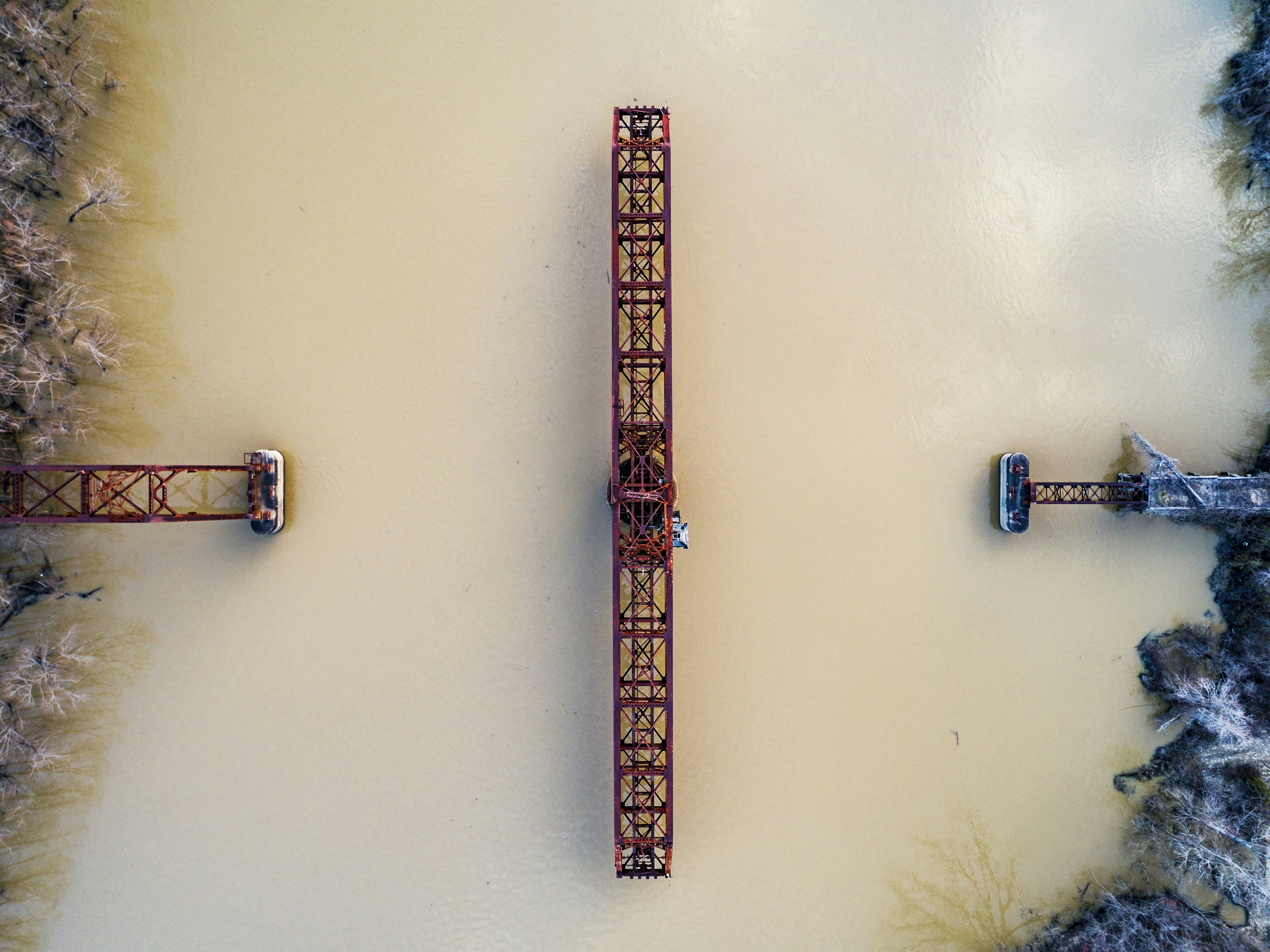 Red Lattice Pier Dividing an Amber River: A Symmetrical Drone Portrait