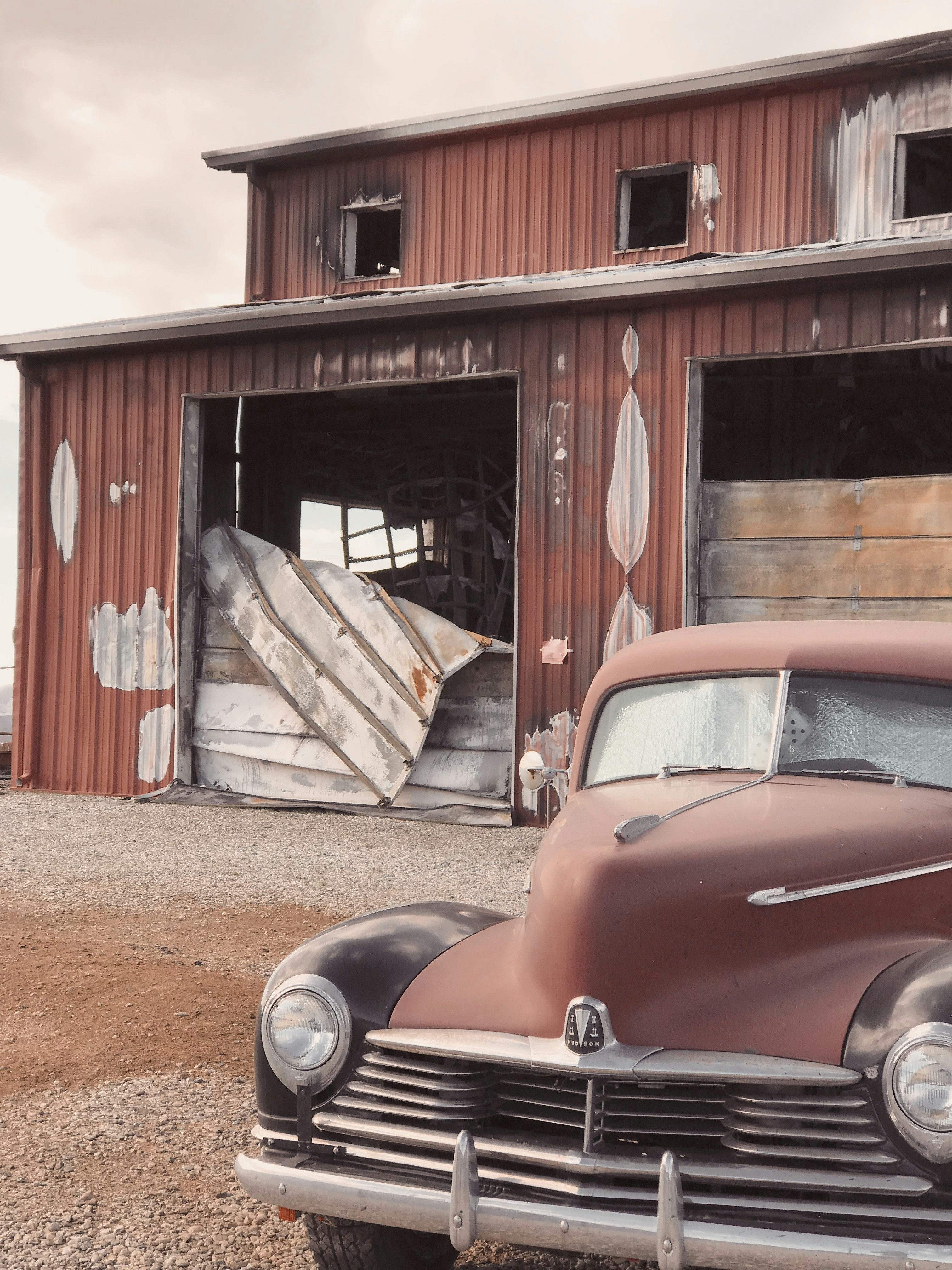 Rust-Red Relic: A Vintage Chevrolet Guarded by a Weathered Barn