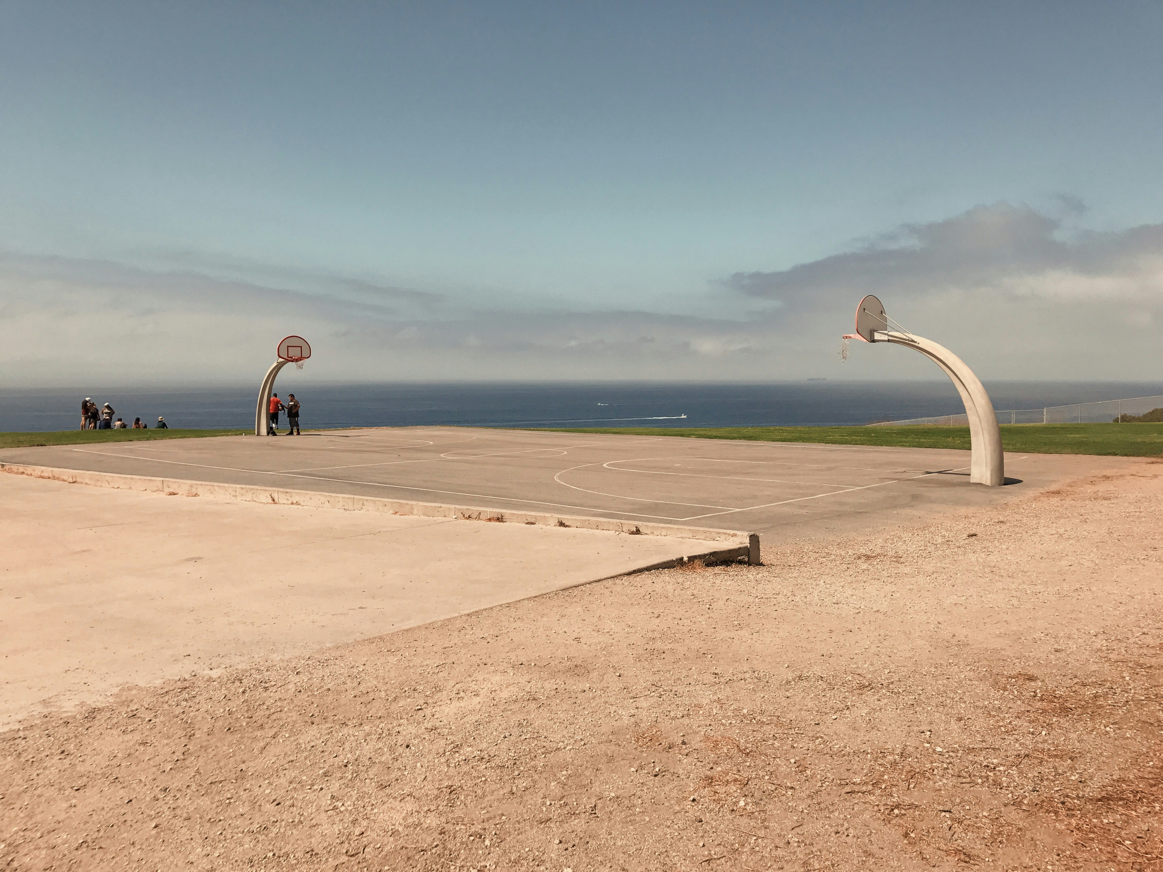 Basketball court overlooking the ocean under a clear blue sky.