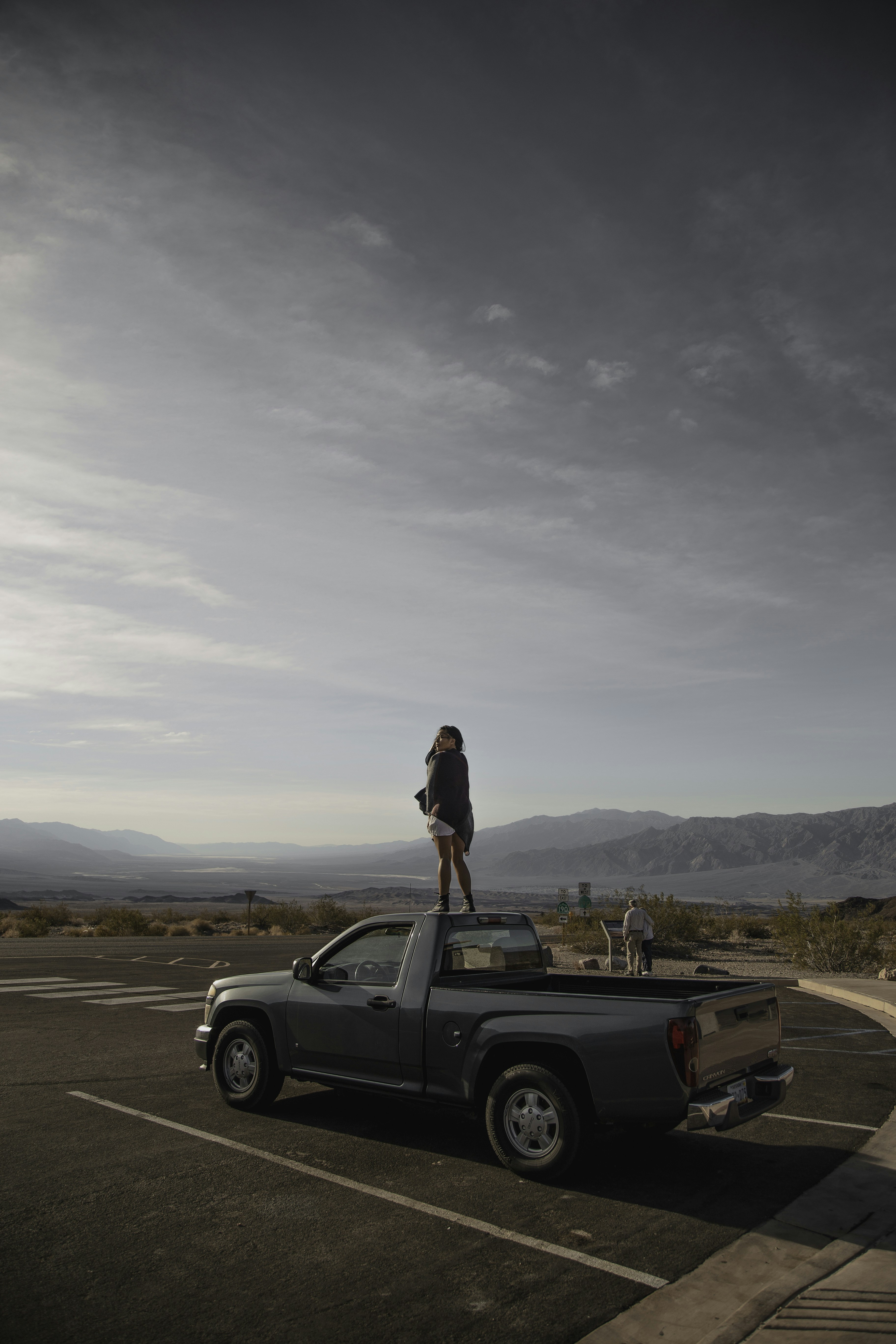 Standpoint on Steel: A Woman Tops a Pickup Against Desert and Mountain Vista